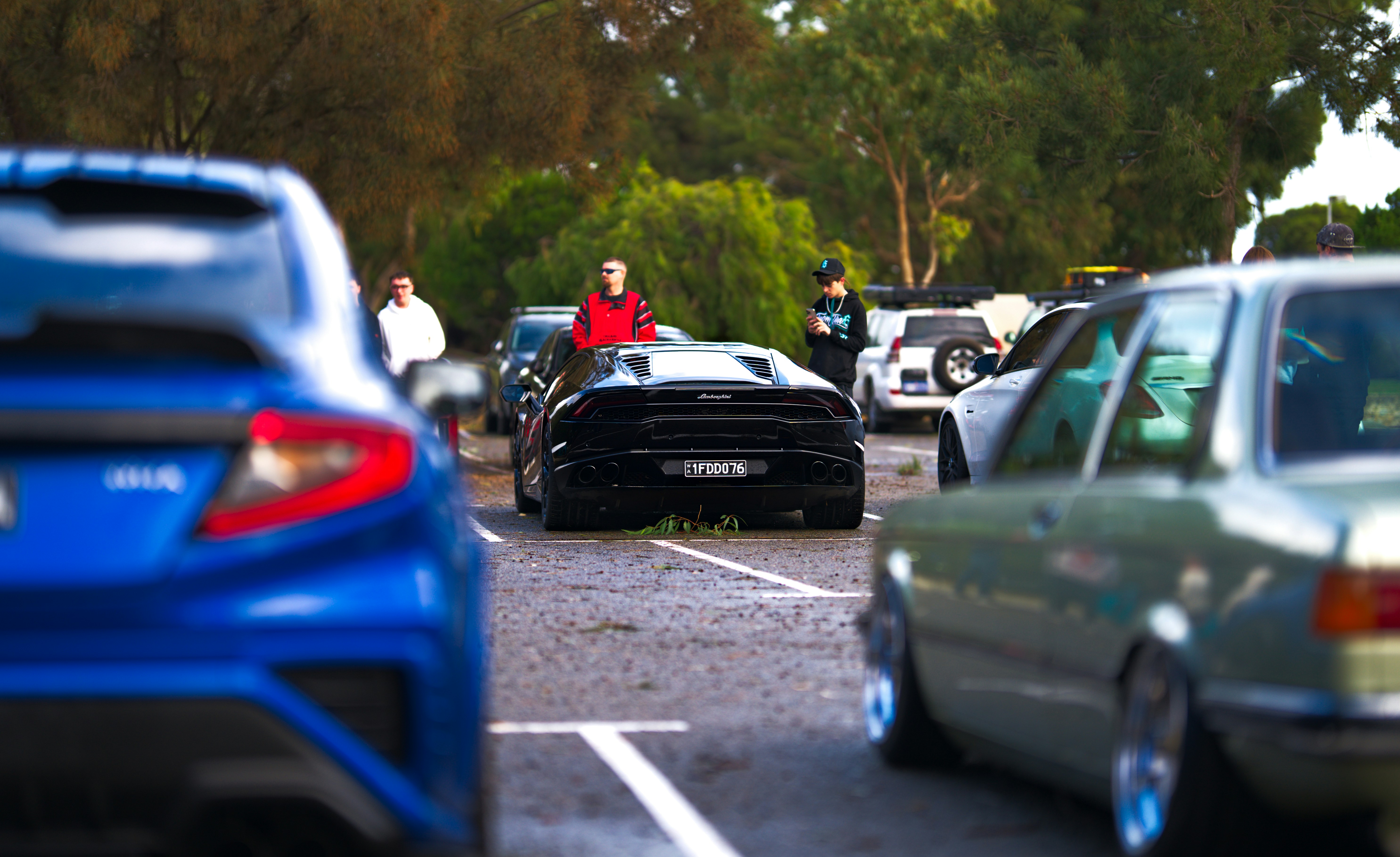 In-Line Standoff: A Black Muscle Car Faces Off Among Sedans in a Parking Lot Rally
