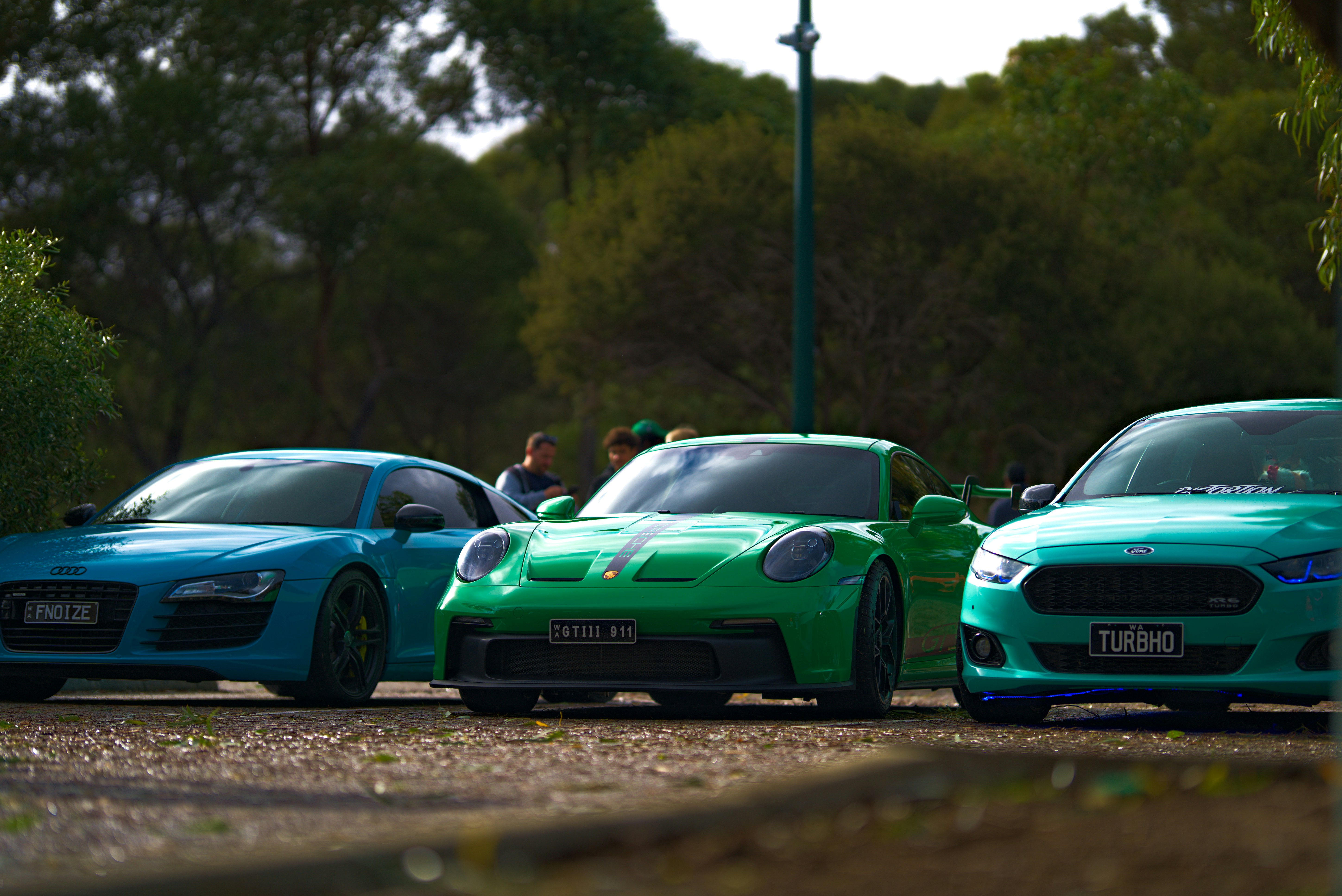 Vibrant trio: three colorful sports cars parked in a sunlit lot