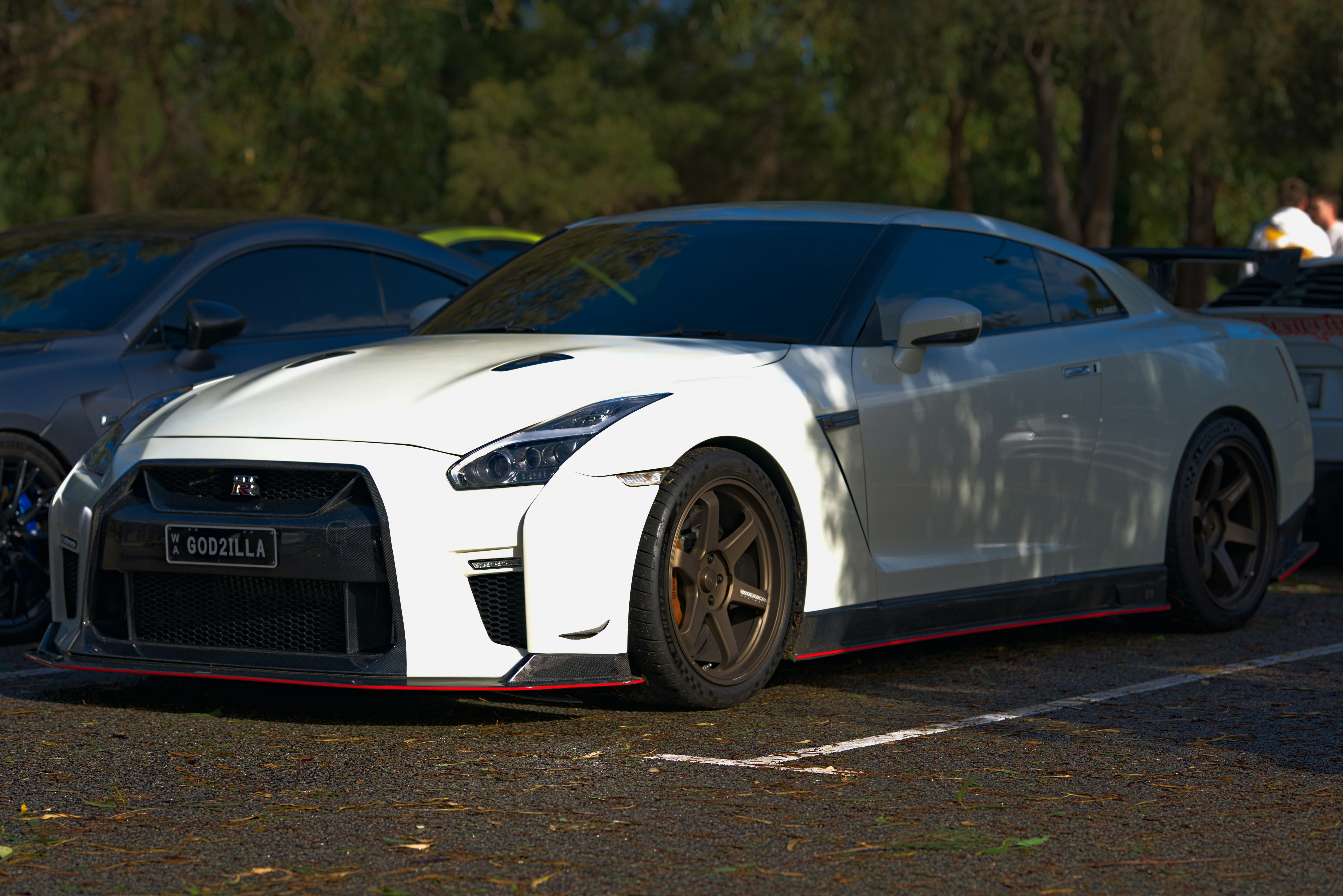 White Nissan GT in a sunlit car show lineup