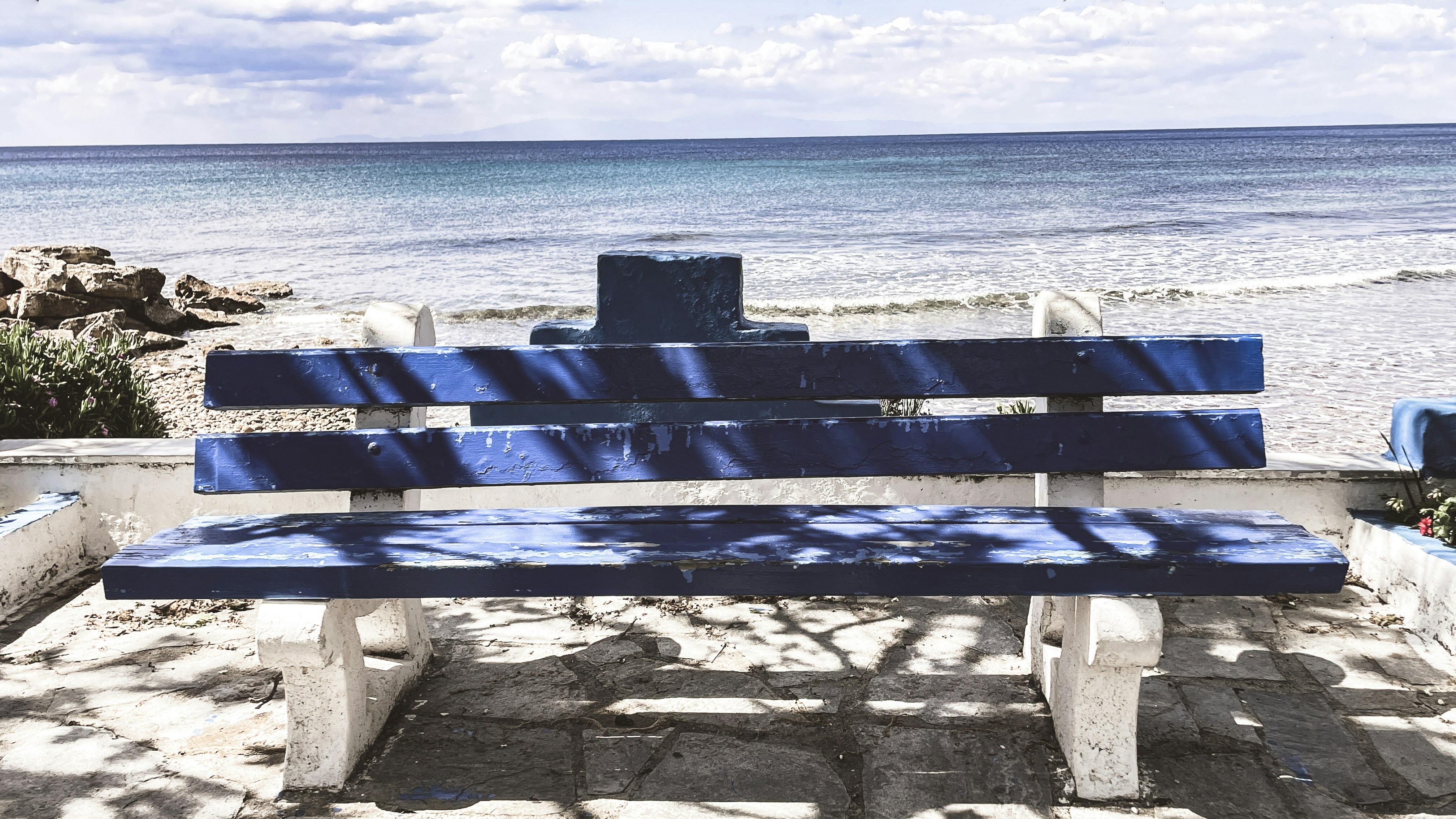 Empty blue bench facing the ocean under a cloudy sky. photo – Free Blue ...