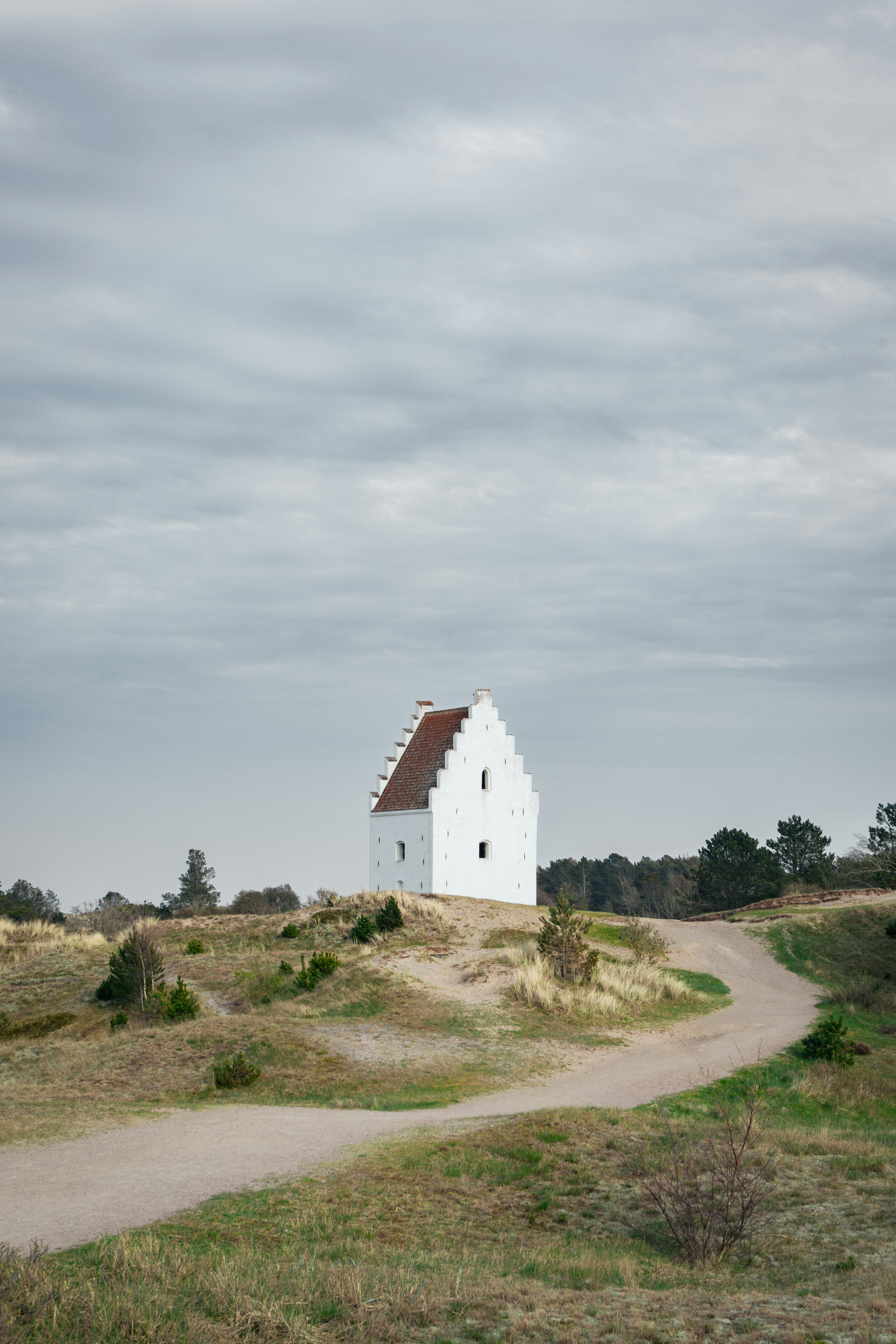 White chapel on wind-swept dunes under a gray ceiling