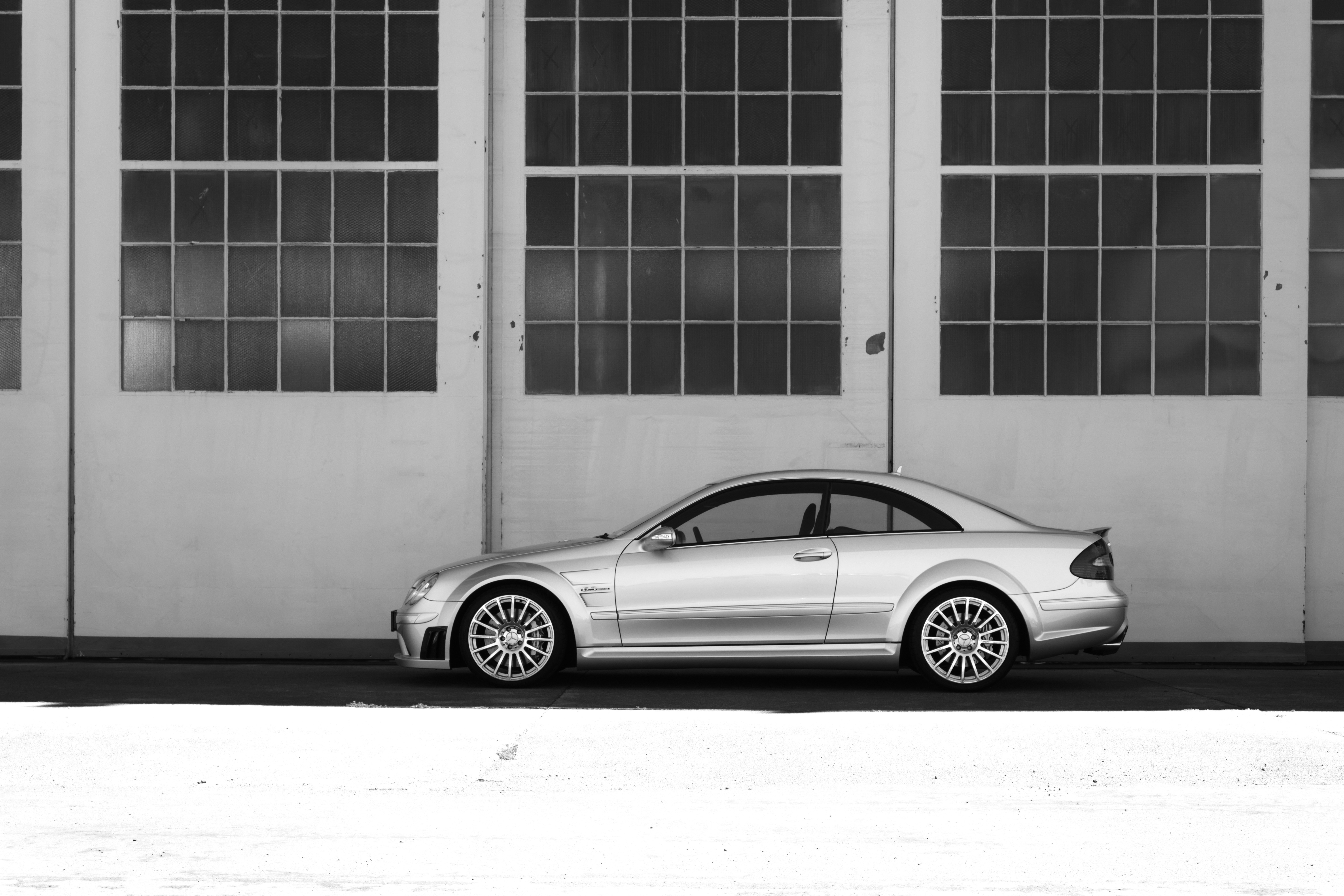 Silent Runner: A Silver Sports Car Anchored Beneath Industrial Windows