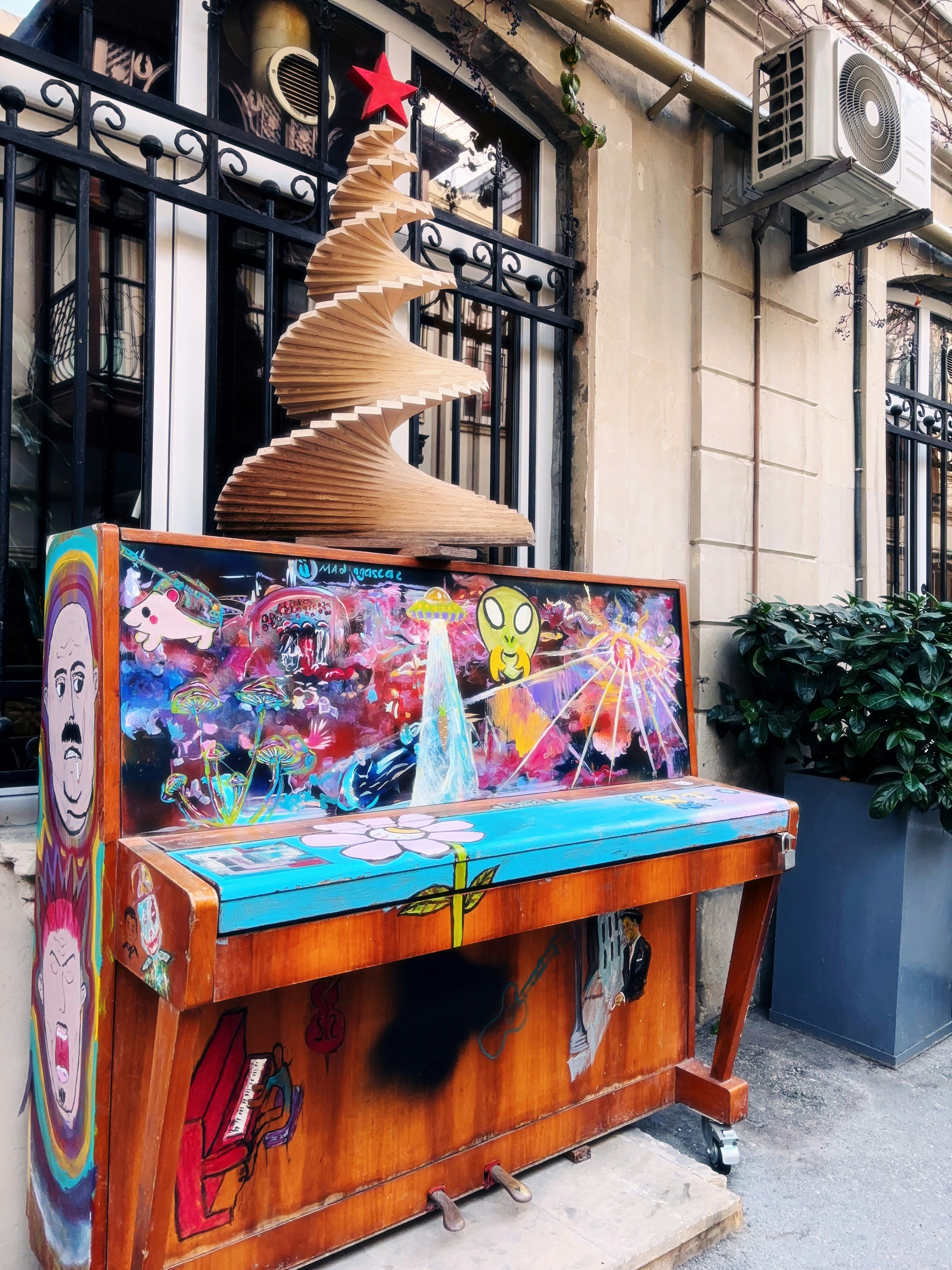Colorful Street Piano Beneath a Spiraling Wooden Christmas Tree