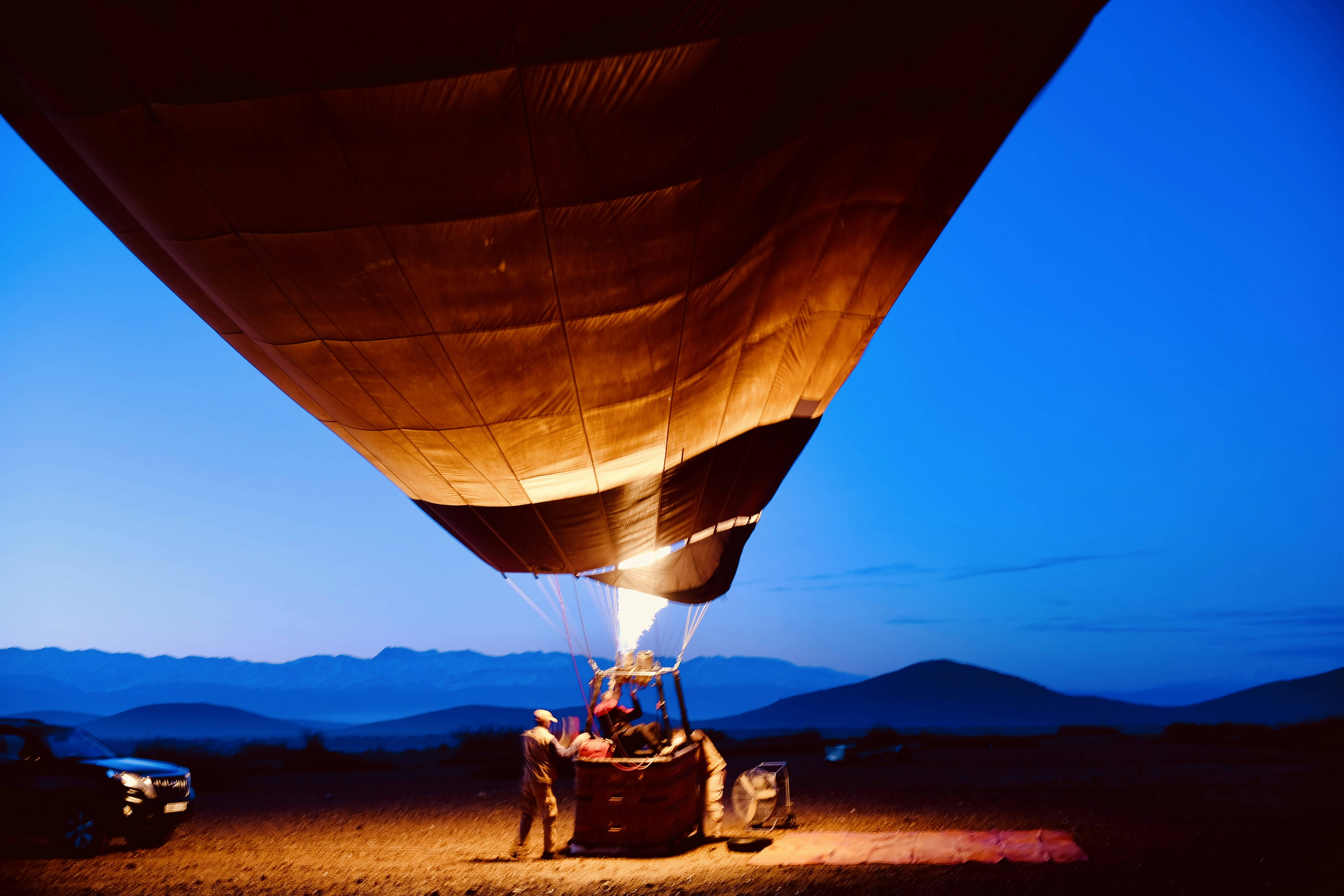 Balloon Lift at Dusk: A Crew Prepares Under a Reddish Glider