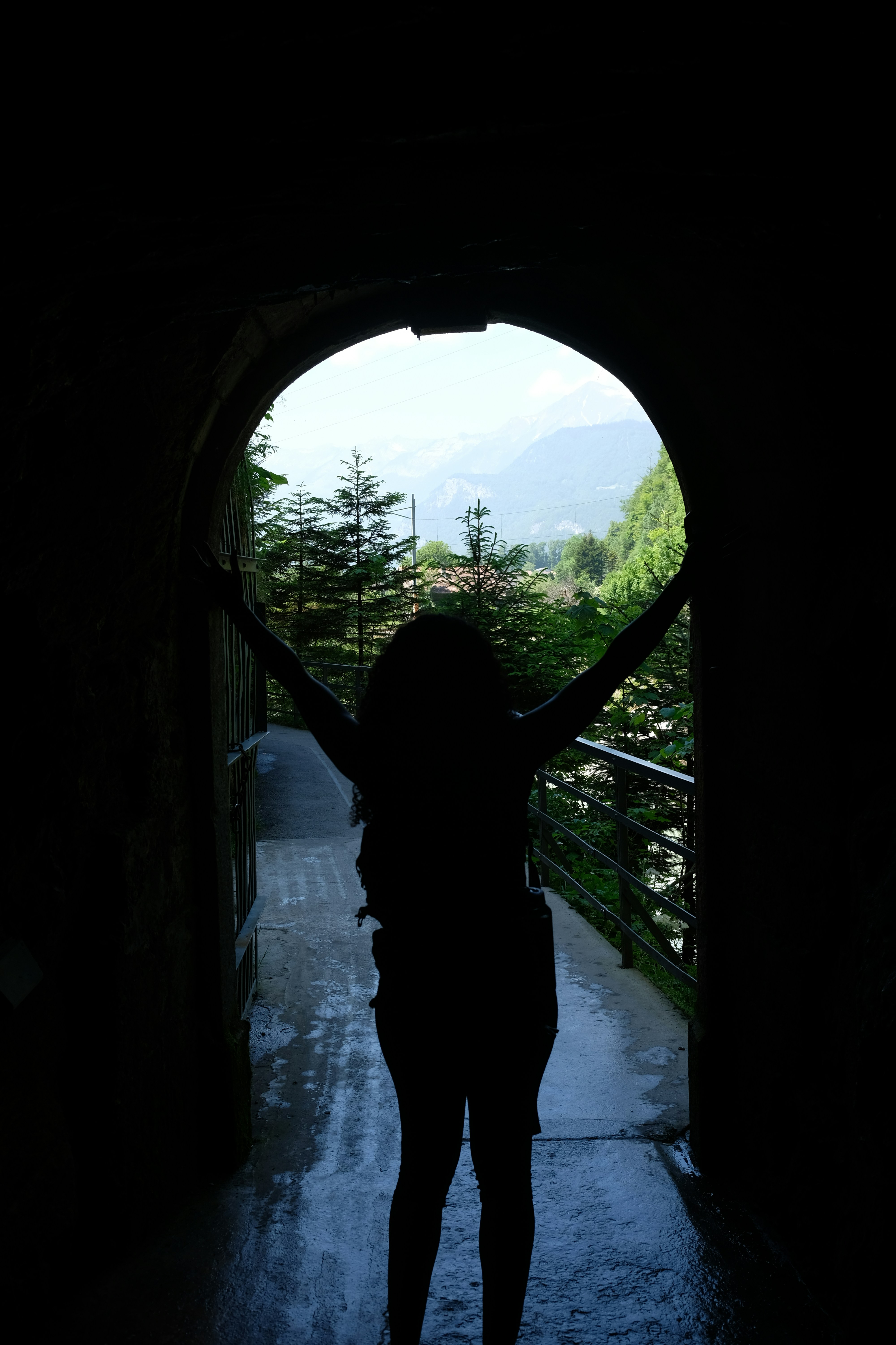  silhouette in a sunlit tunnel opening overlooking the valley