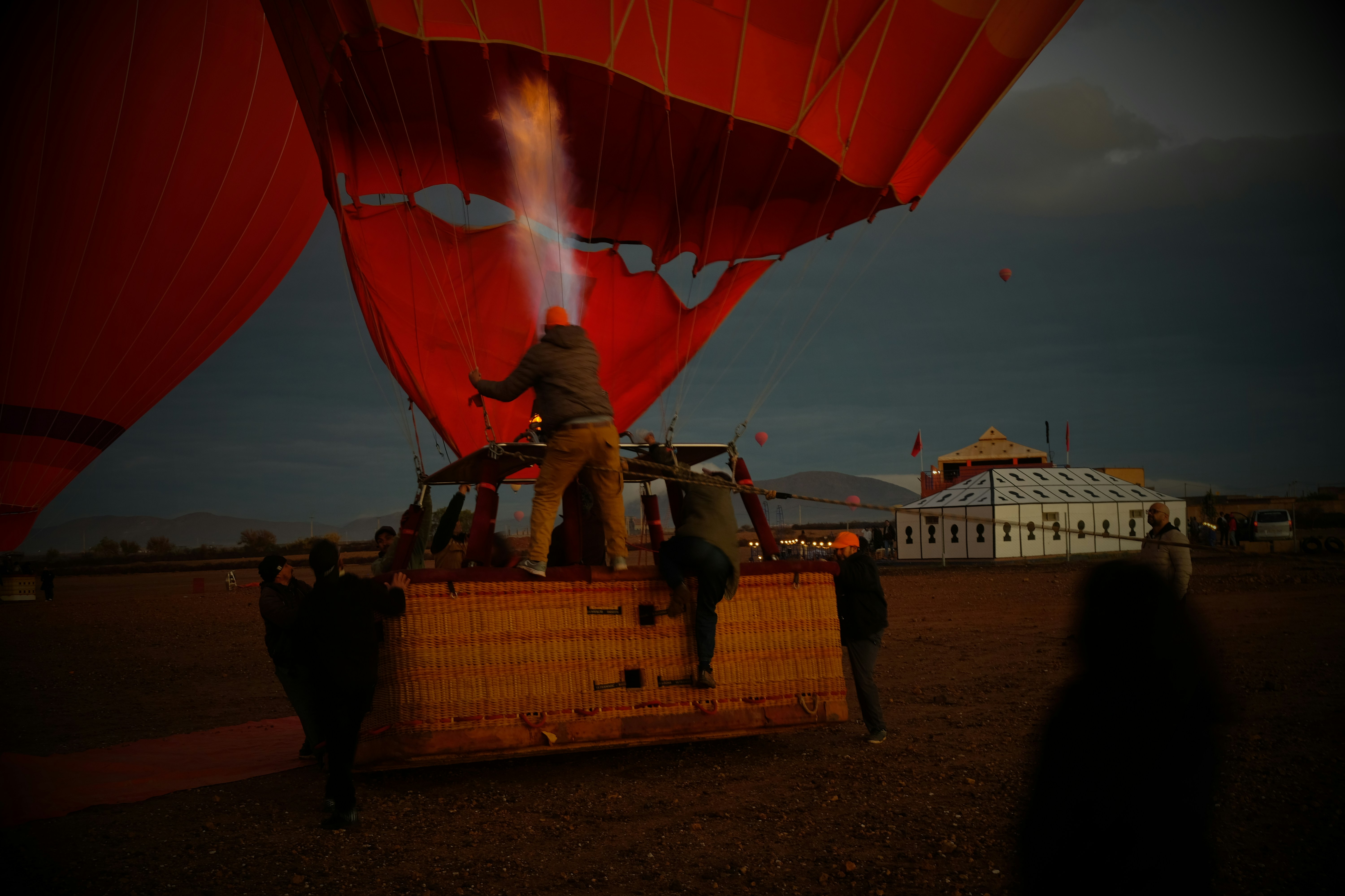 People preparing a hot air balloon with a fiery burner.