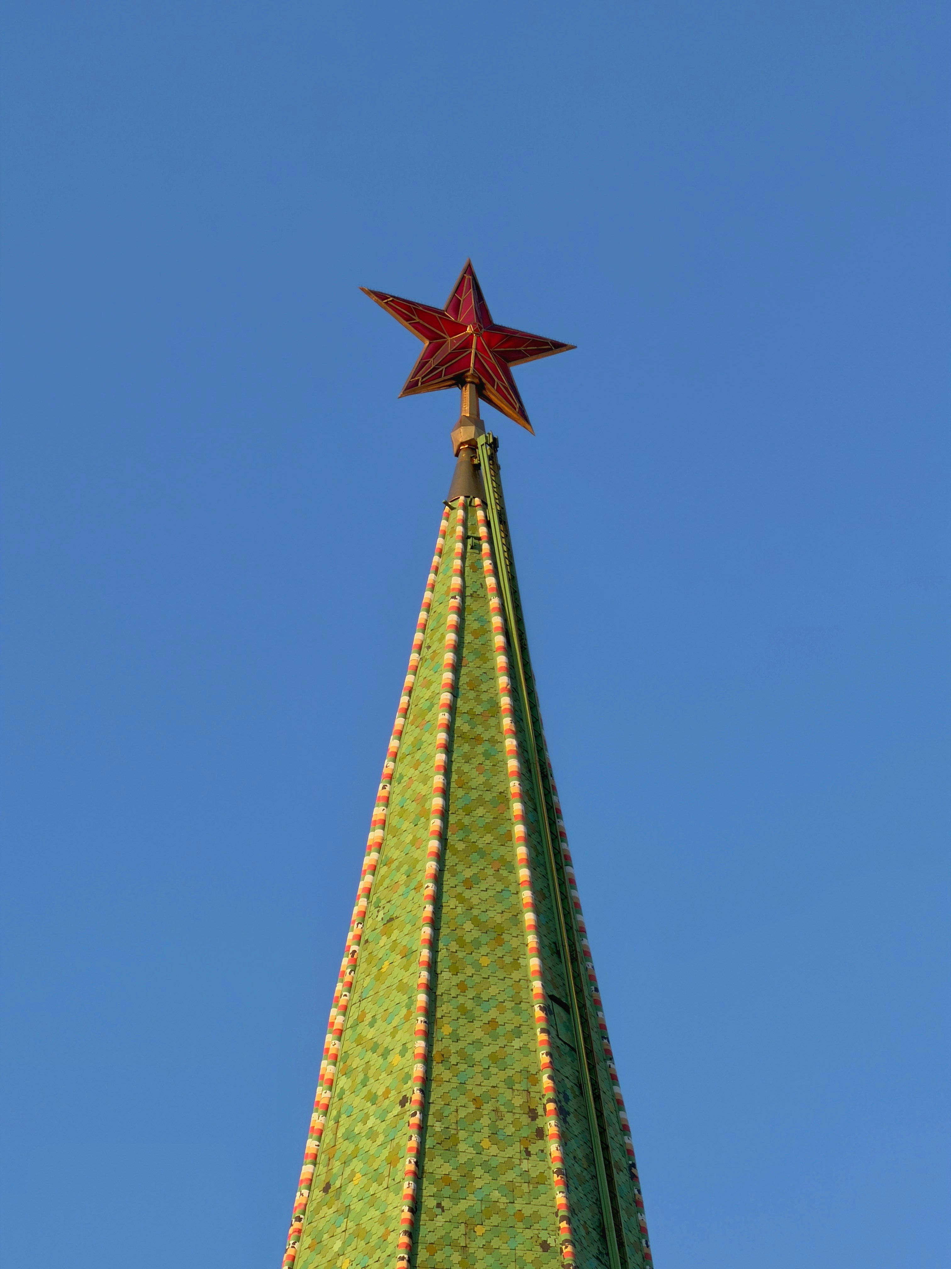 Star atop a slender green spire under a clear blue sky