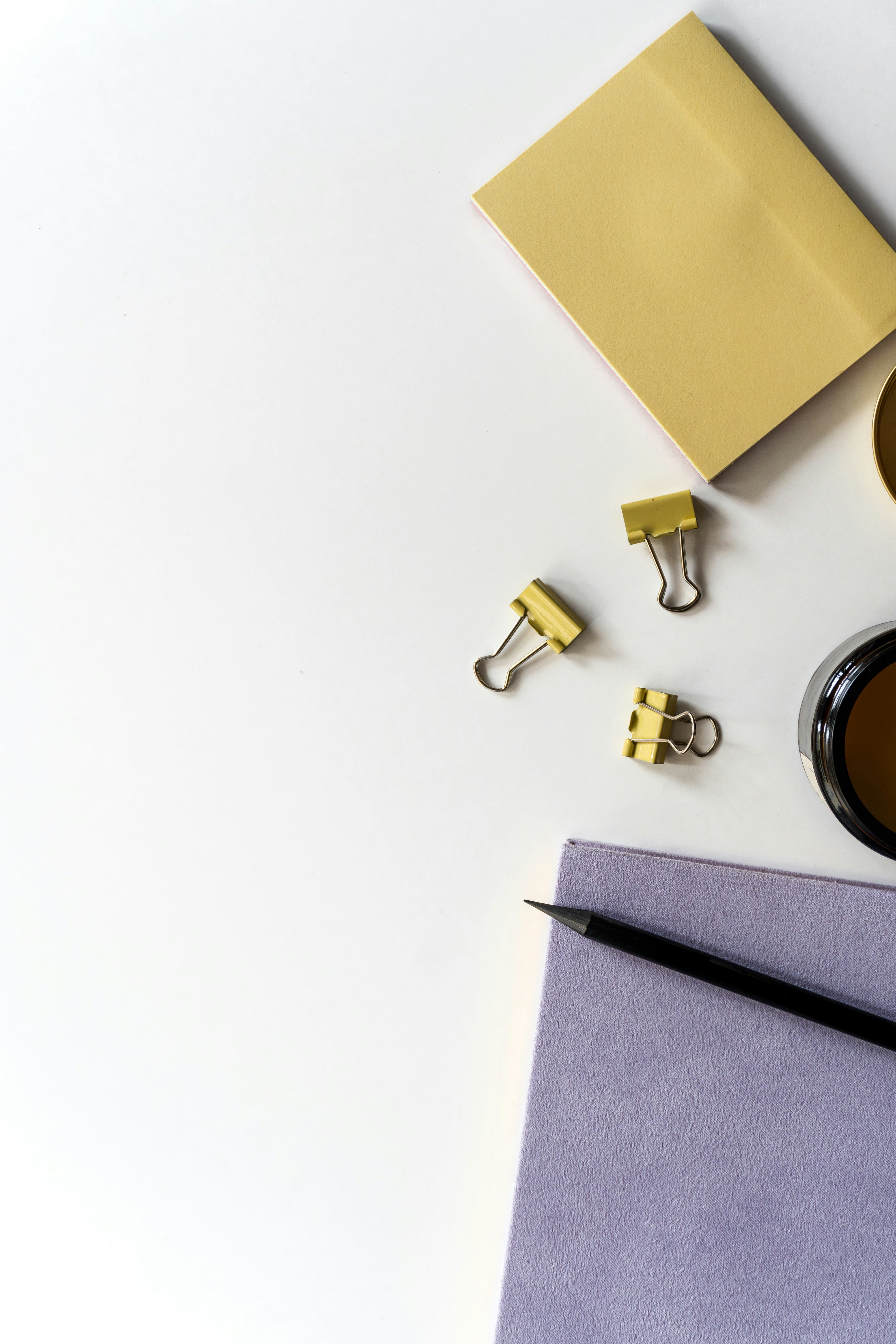 Yellow and purple notebooks with gold clips and a pencil.