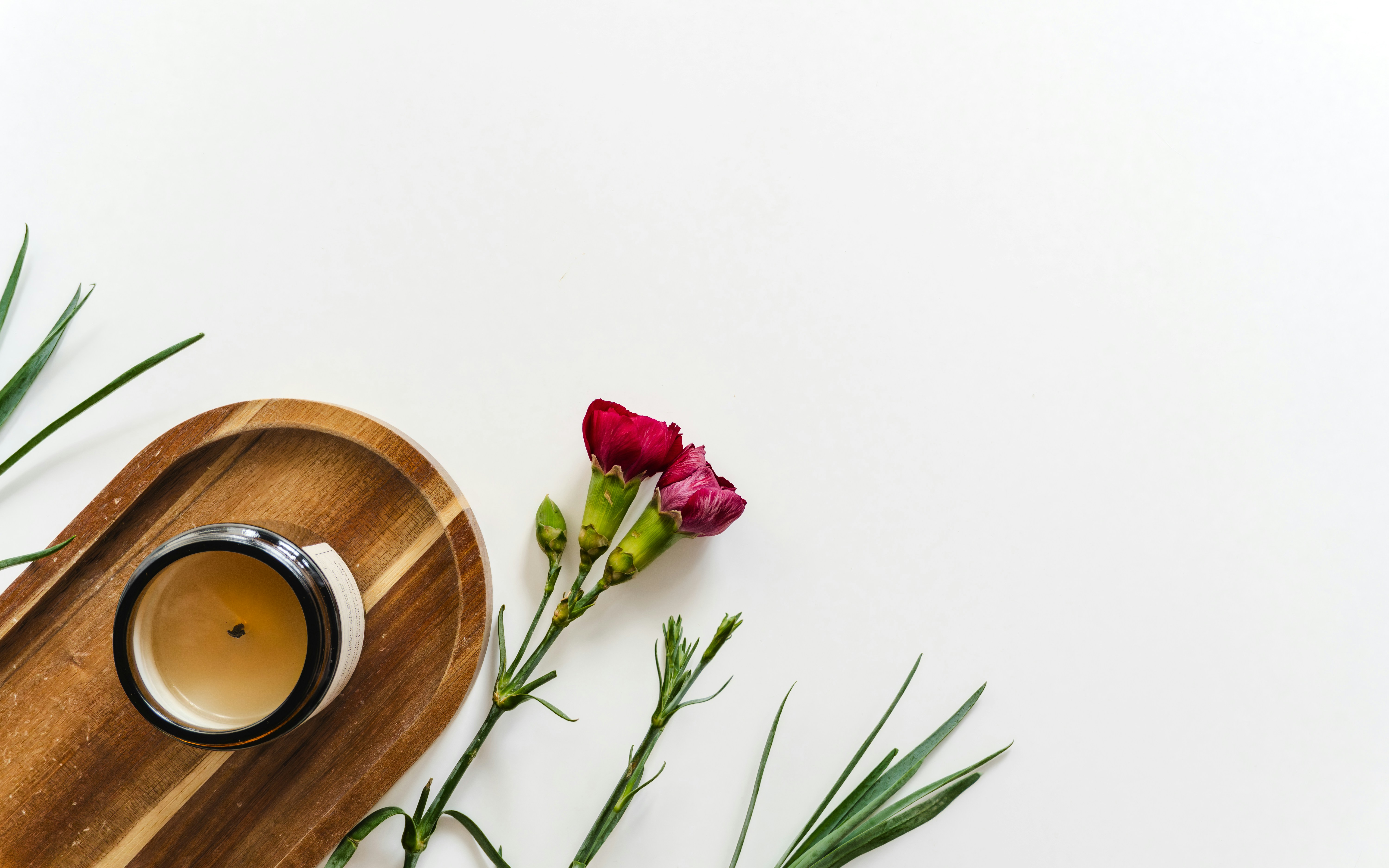 Flat lay with red carnations, wooden stand, and candle creating a warm and elegant composition. Ideal for romantic, memorial, and decorative concepts.