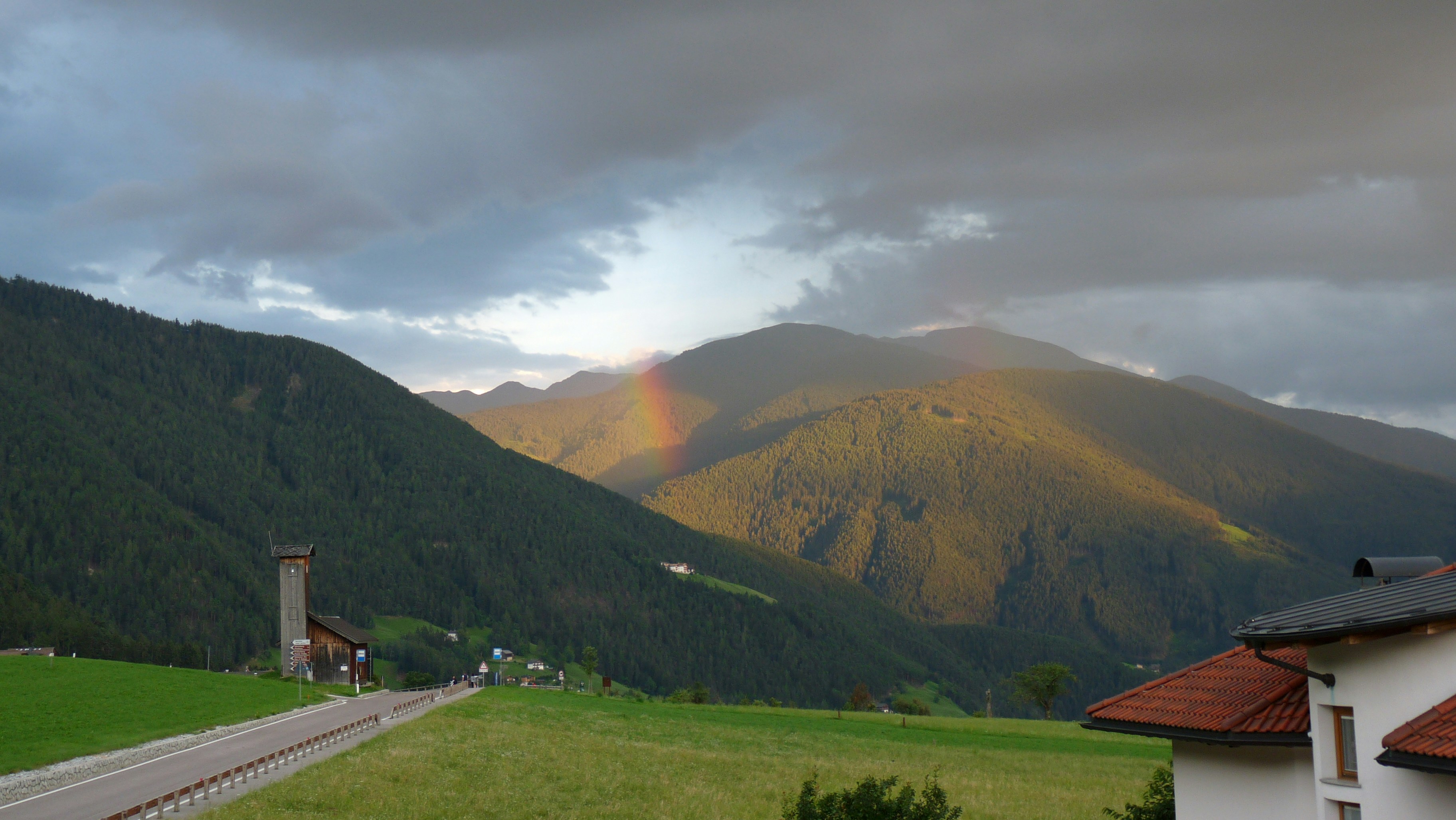 Rainbow Between Mountain Ridges Over a Rural Valley