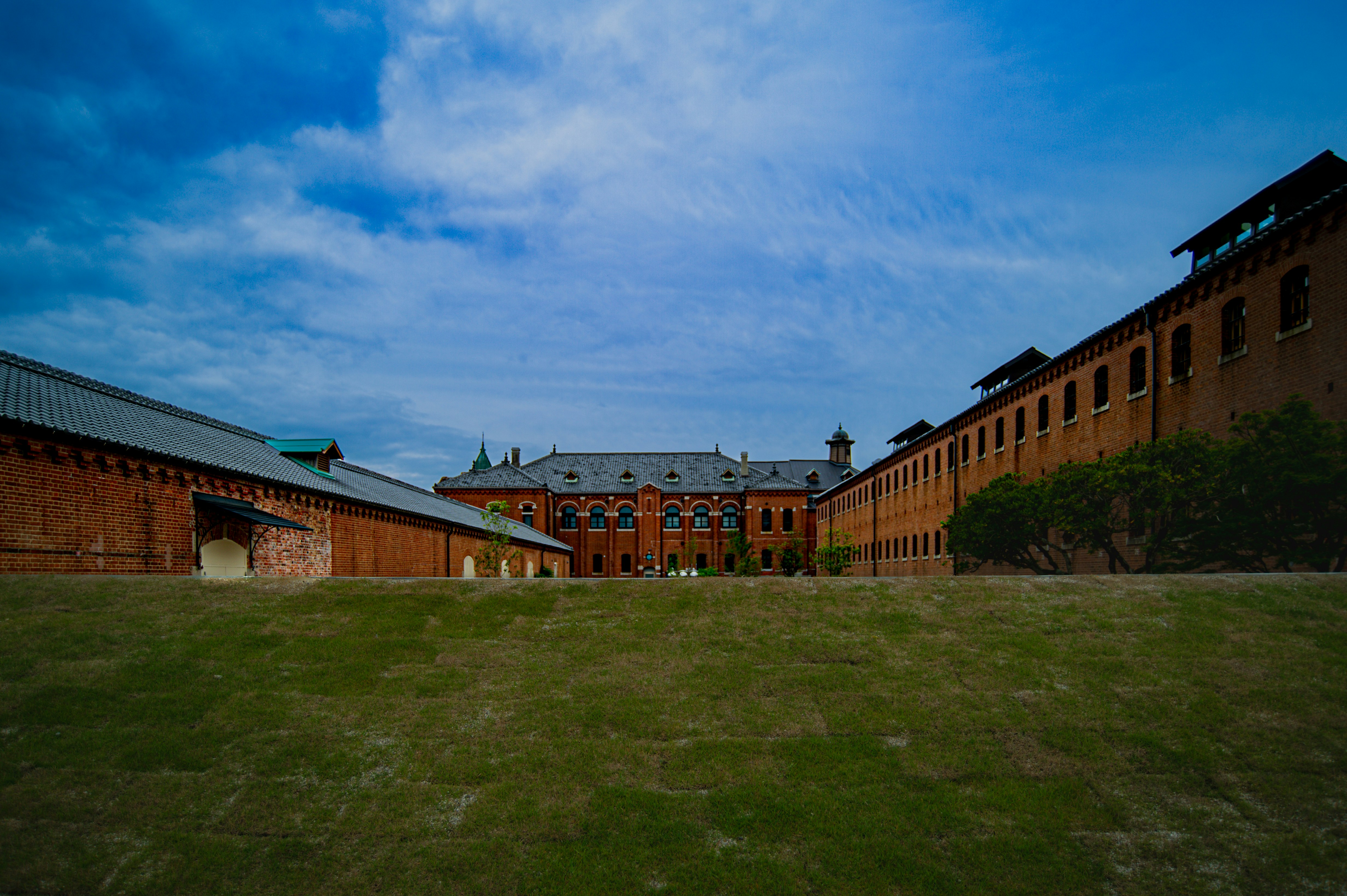 Historic brick architecture with a central building and green field.