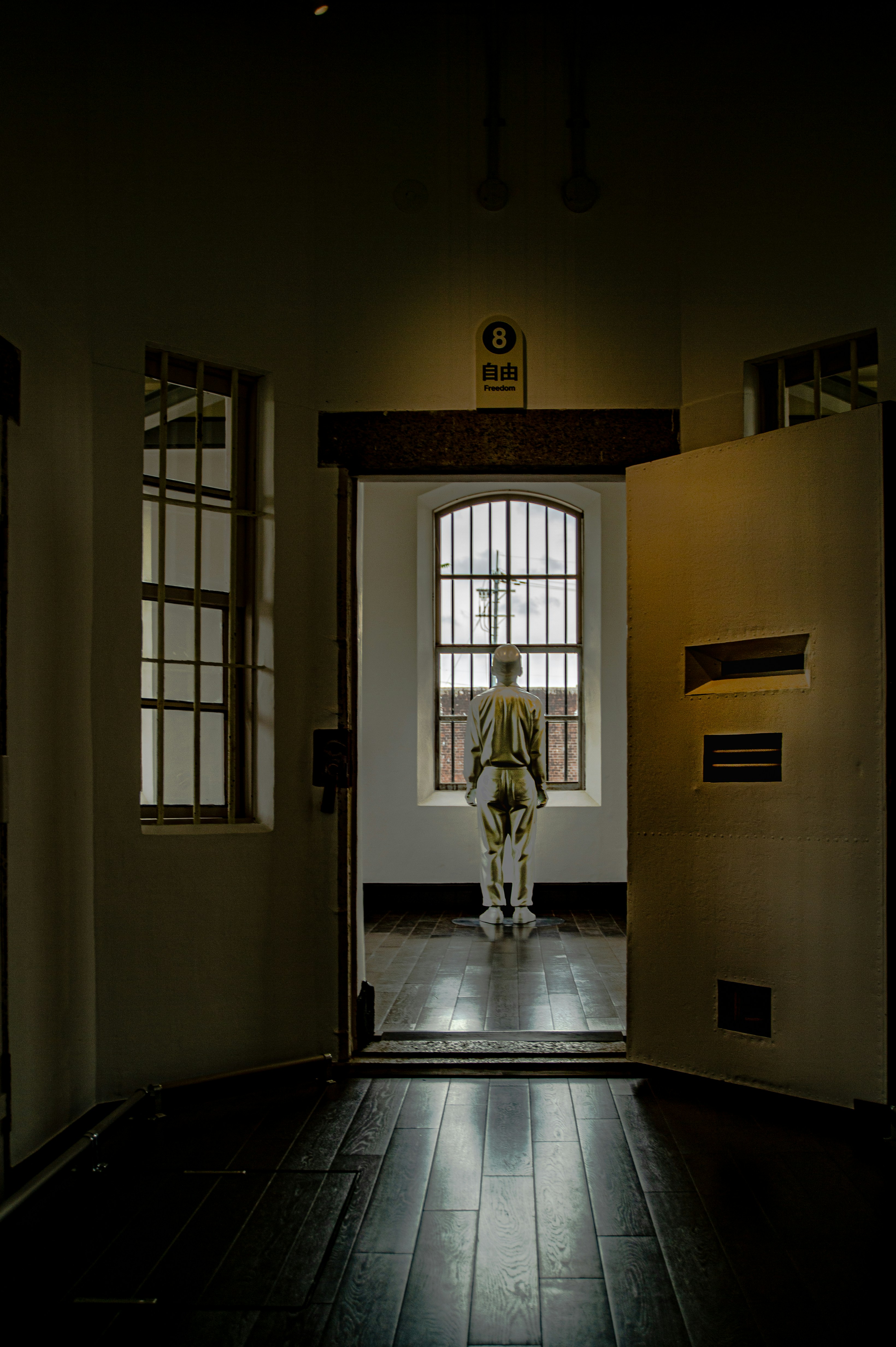 Quiet Exit: A Figure in a Dim Corridor Reaching Toward the Light