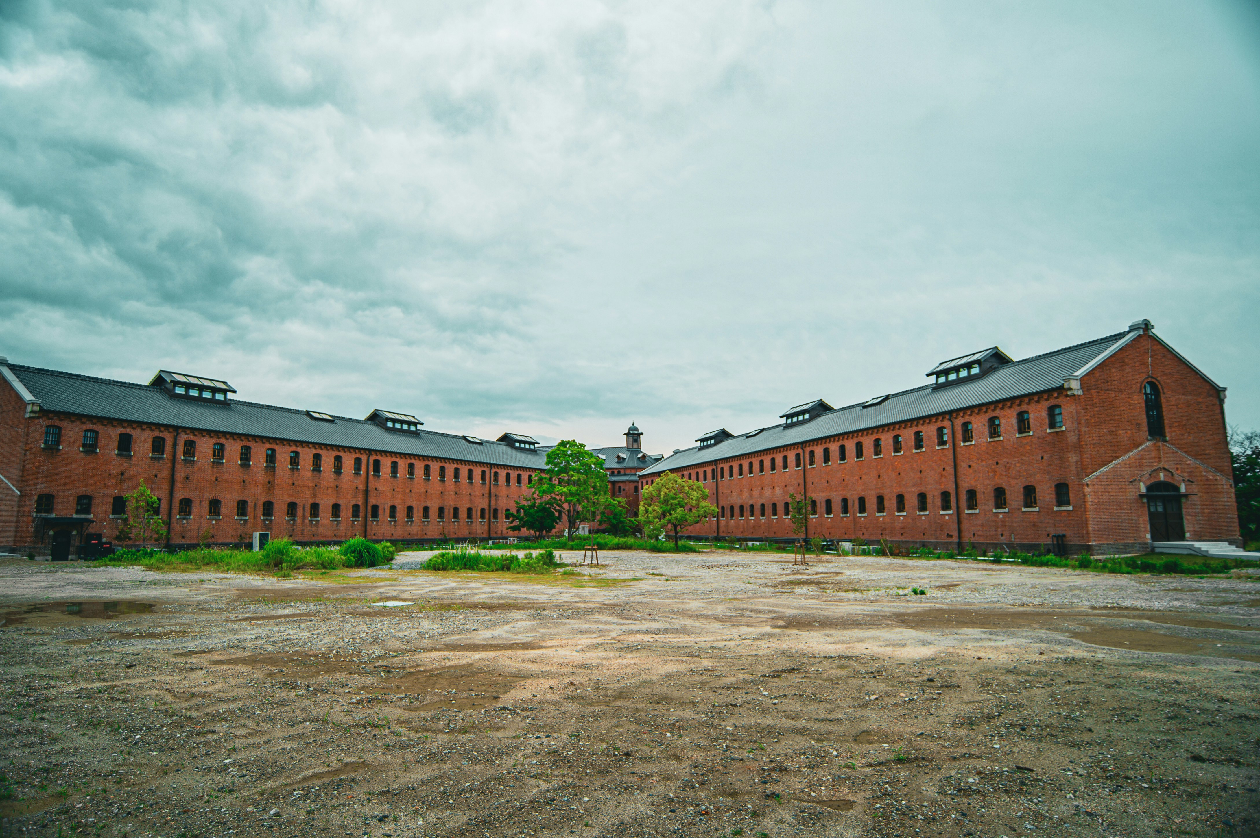 An Abandoned Brick Complex Framing a Quiet Center of Green