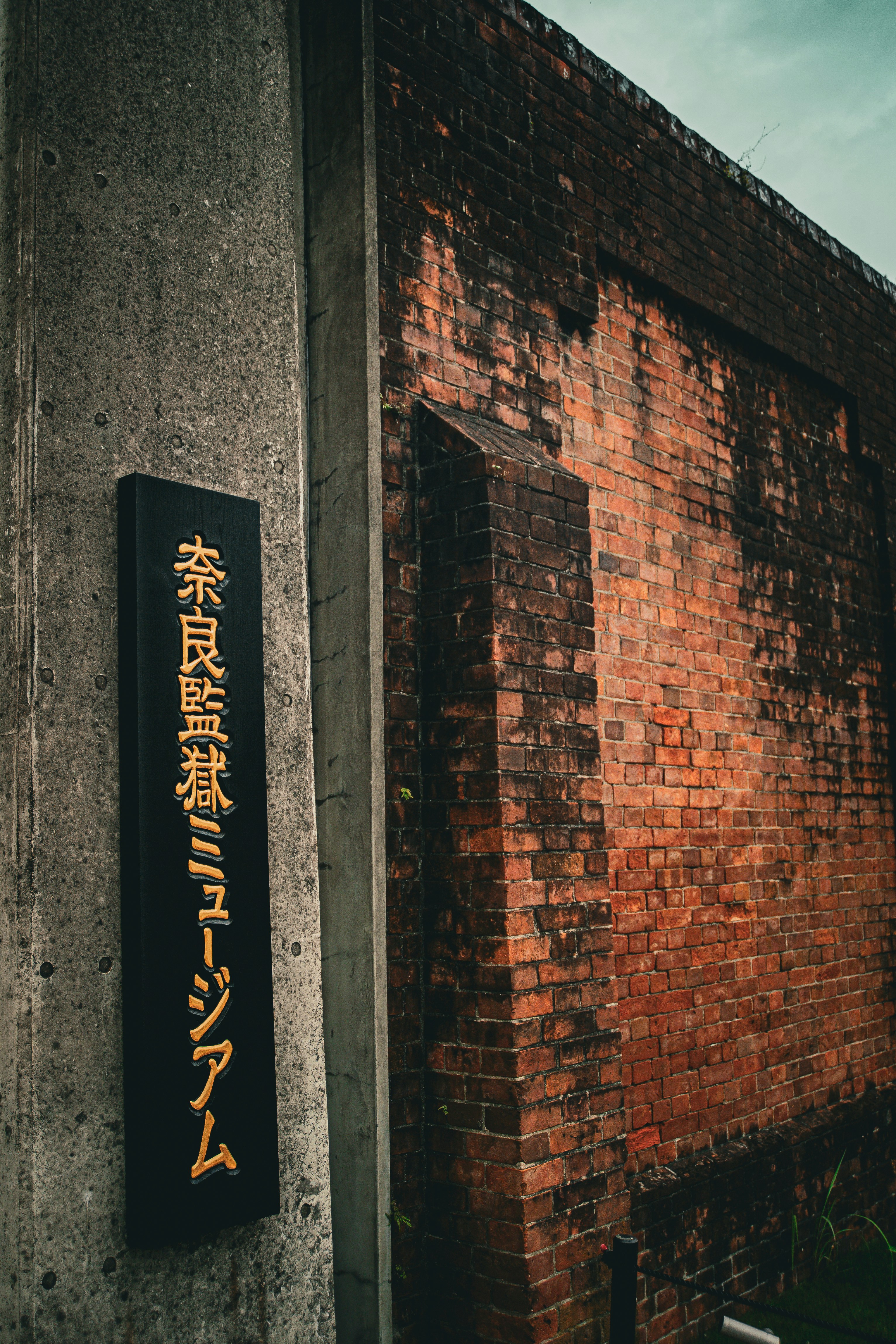 Bricked Gatekeeper: Vertical Sign Against an Aged Wall