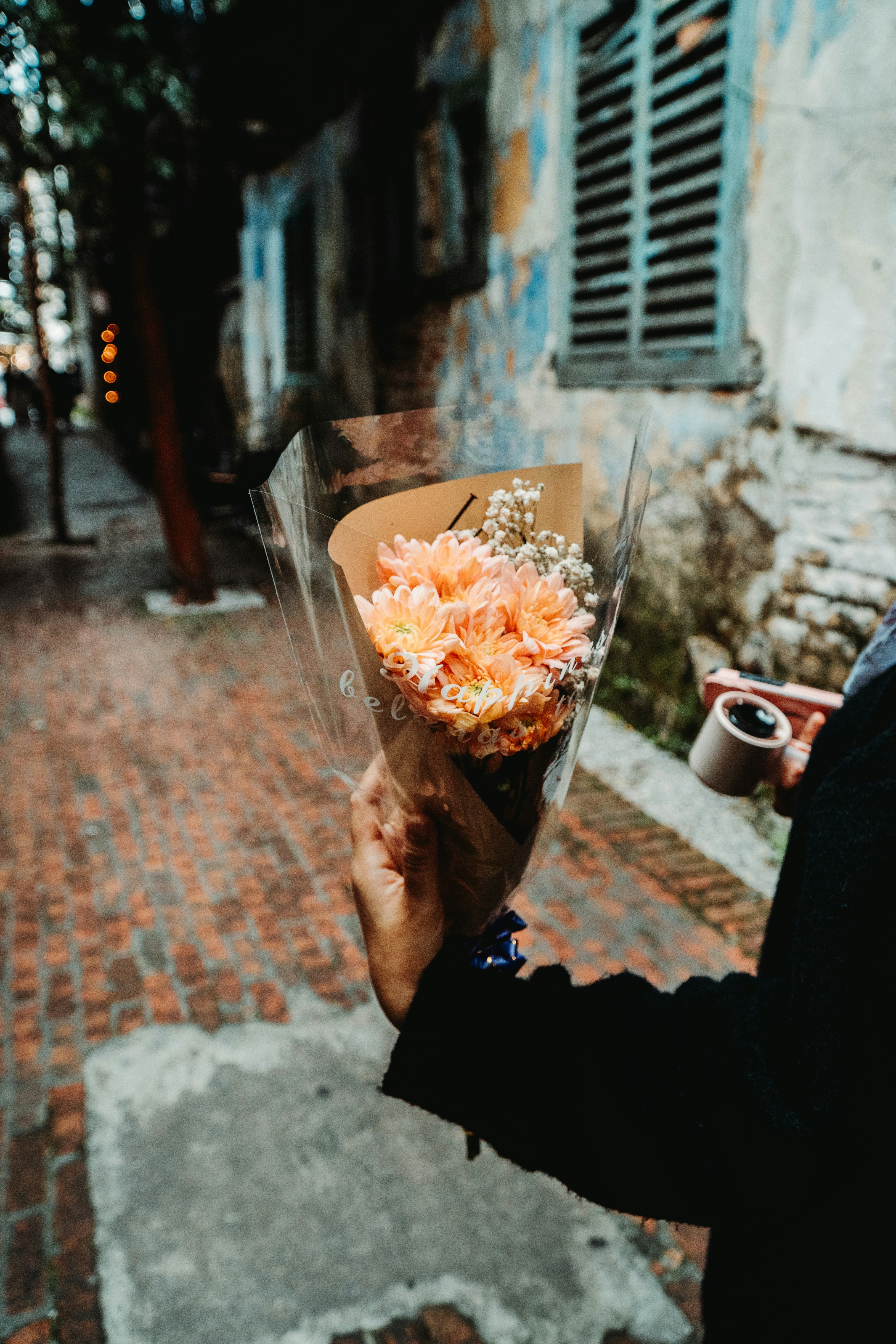 Bouquet Lift: Peach Blooms Against a Weathered Street