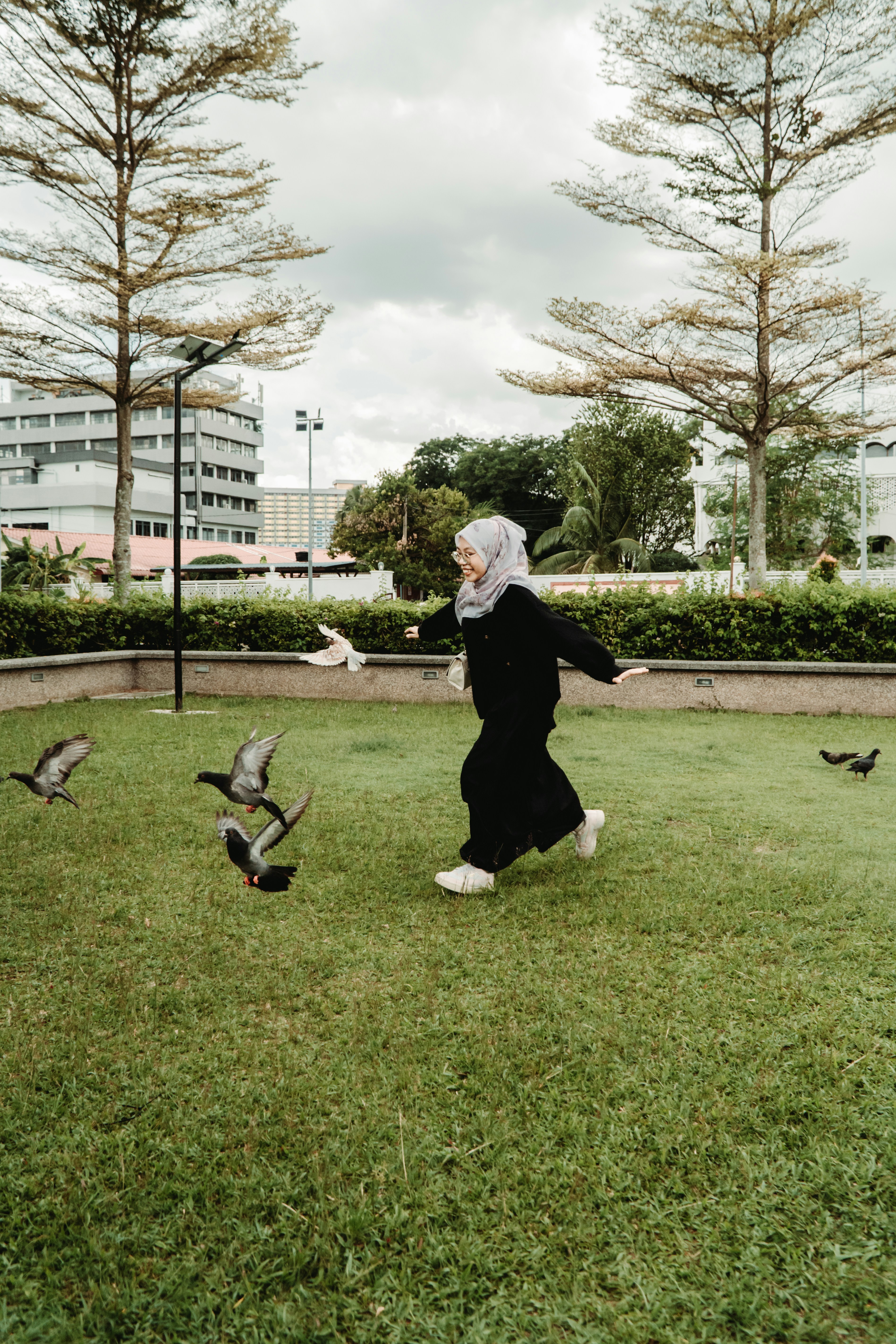 Joyful Sprint in the Park: A Hijab-Clad Runner and Pigeons