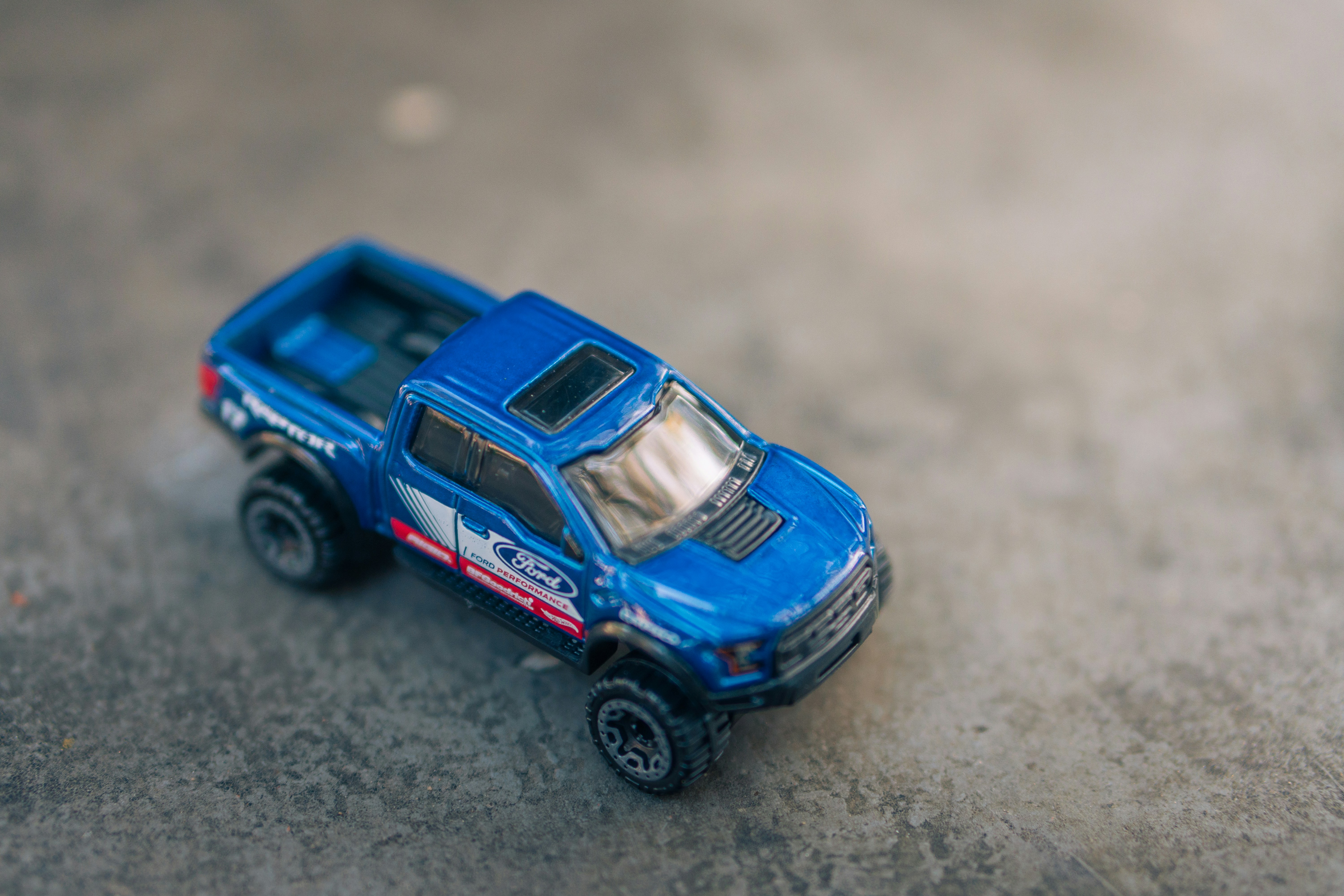 A blue toy pickup truck on a grey surface.