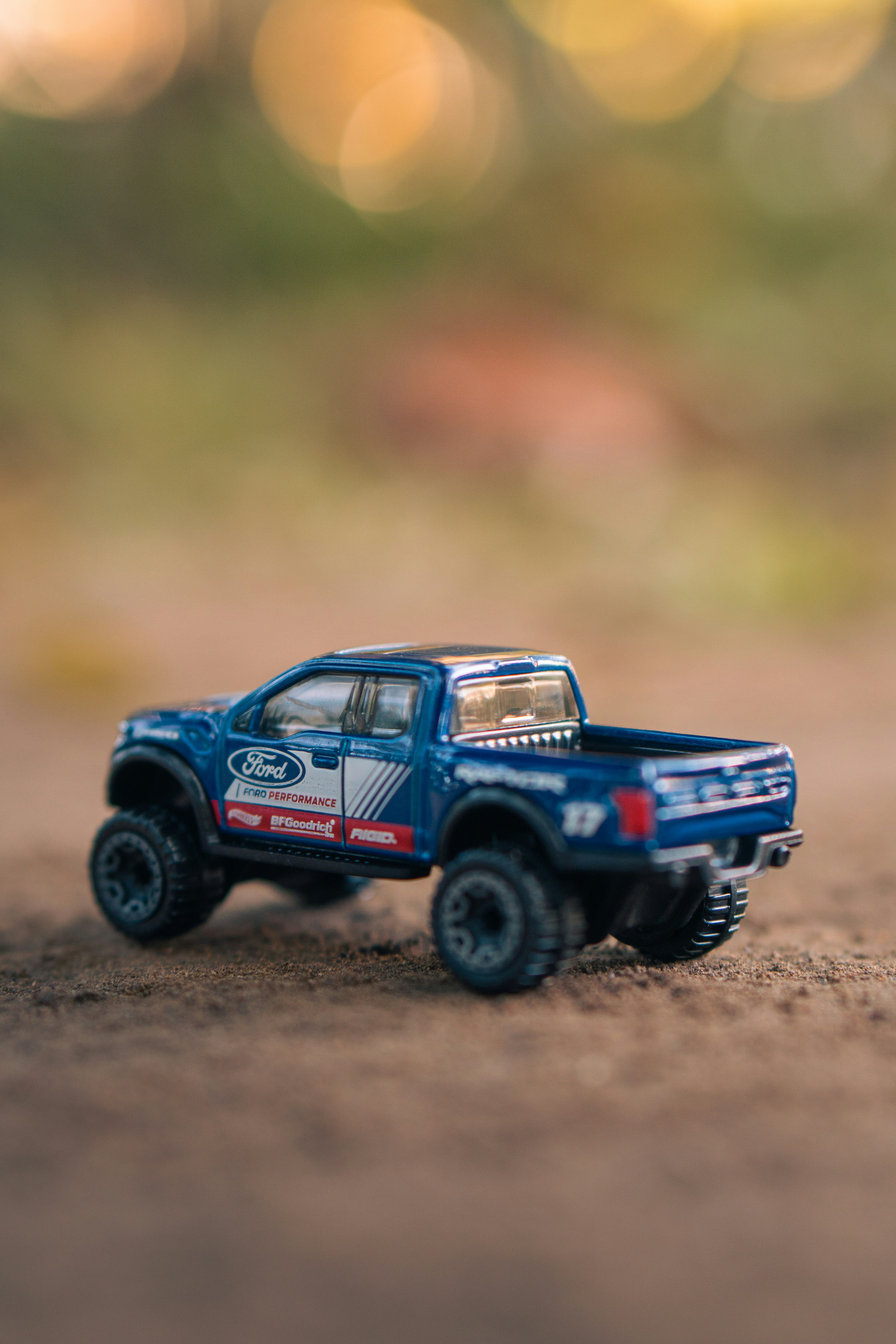 Blue ford toy pickup truck on a dirt surface.