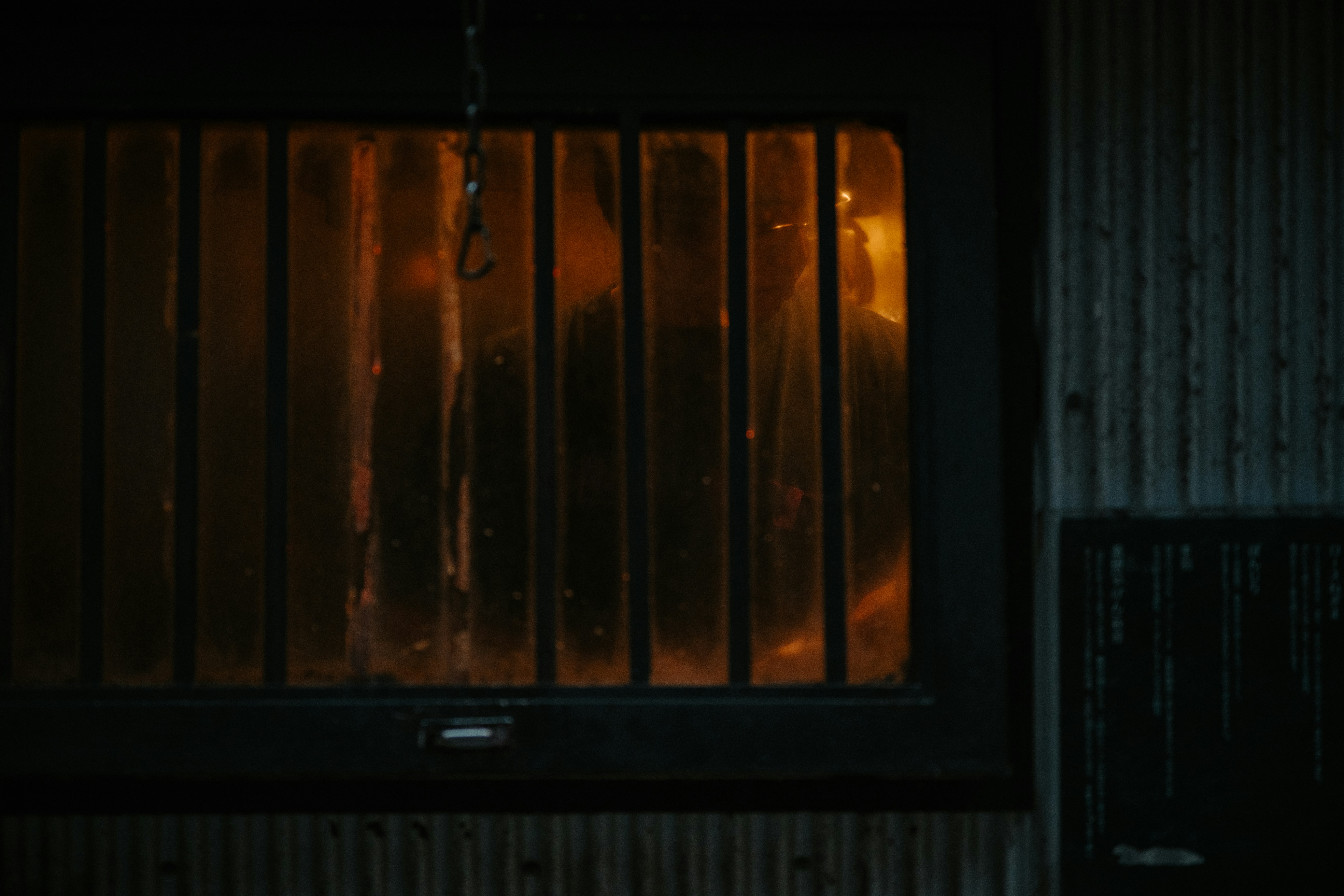A dark window with orange light glowing from within.