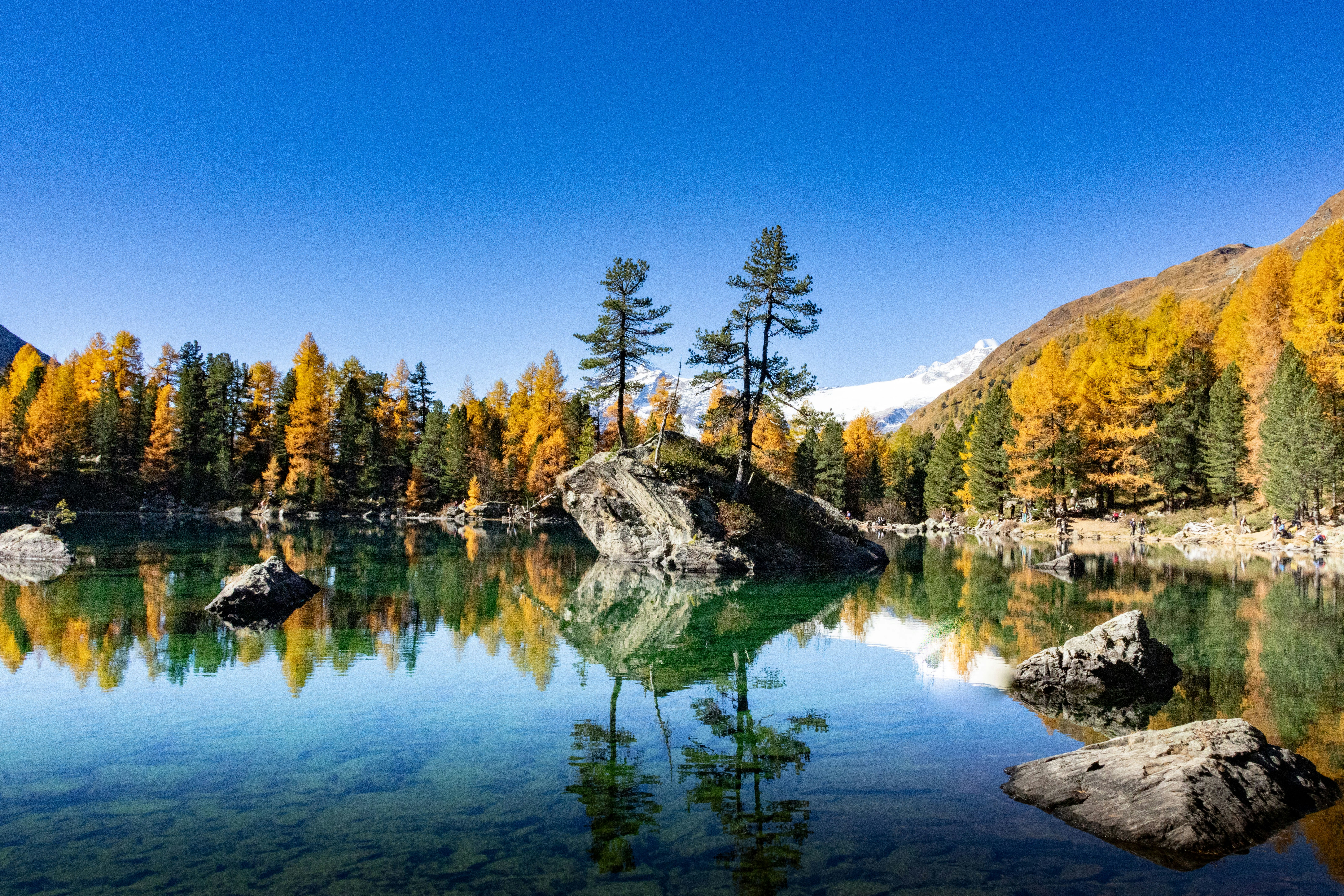 Clear lake with autumn trees and mountain reflections.