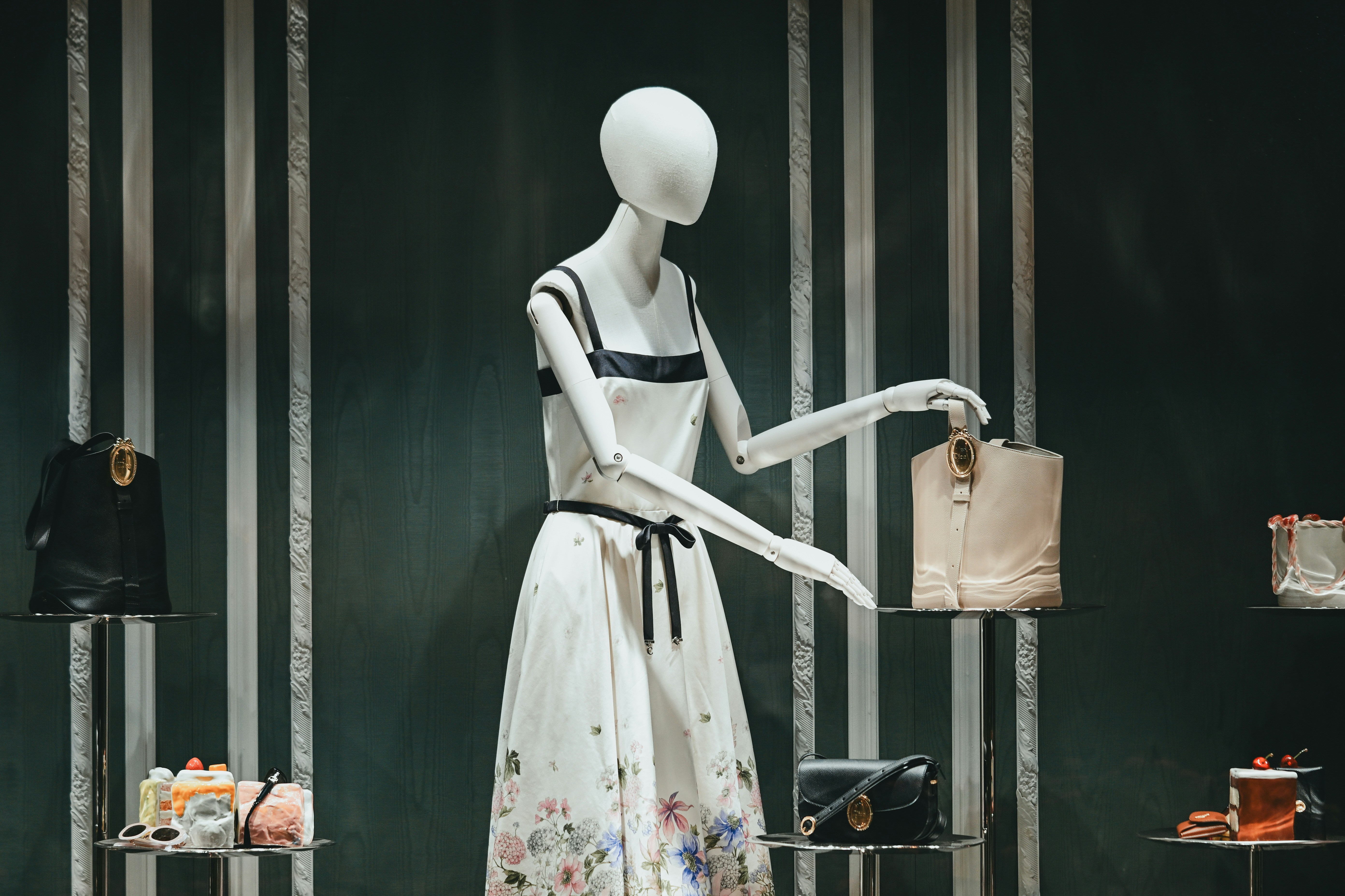 Mannequin in a boutique window, clutching a beige bag amidst a display of accessories
