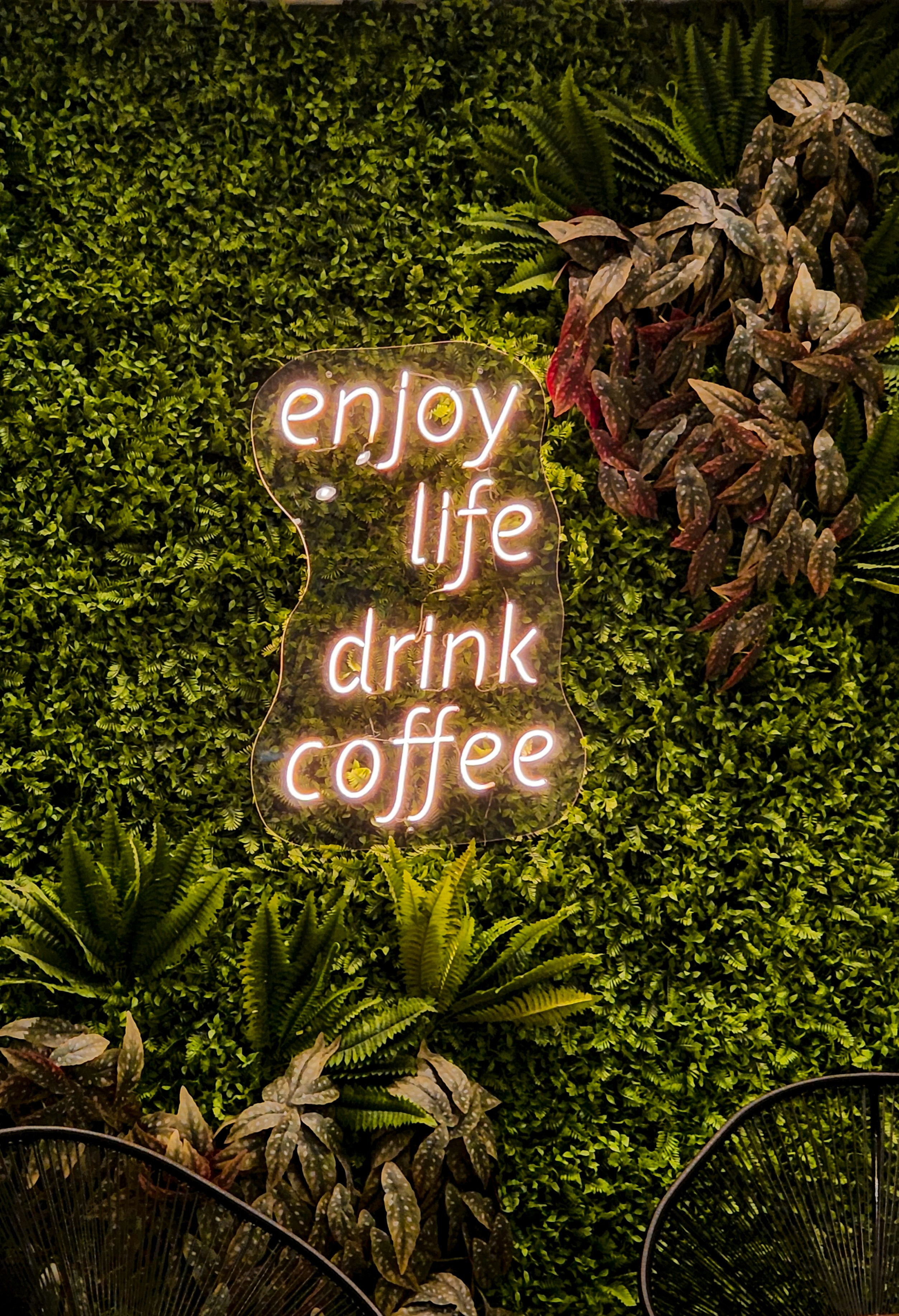 Neon Coffee Bloom: A Sign Catching Firelight Against Green Foliage