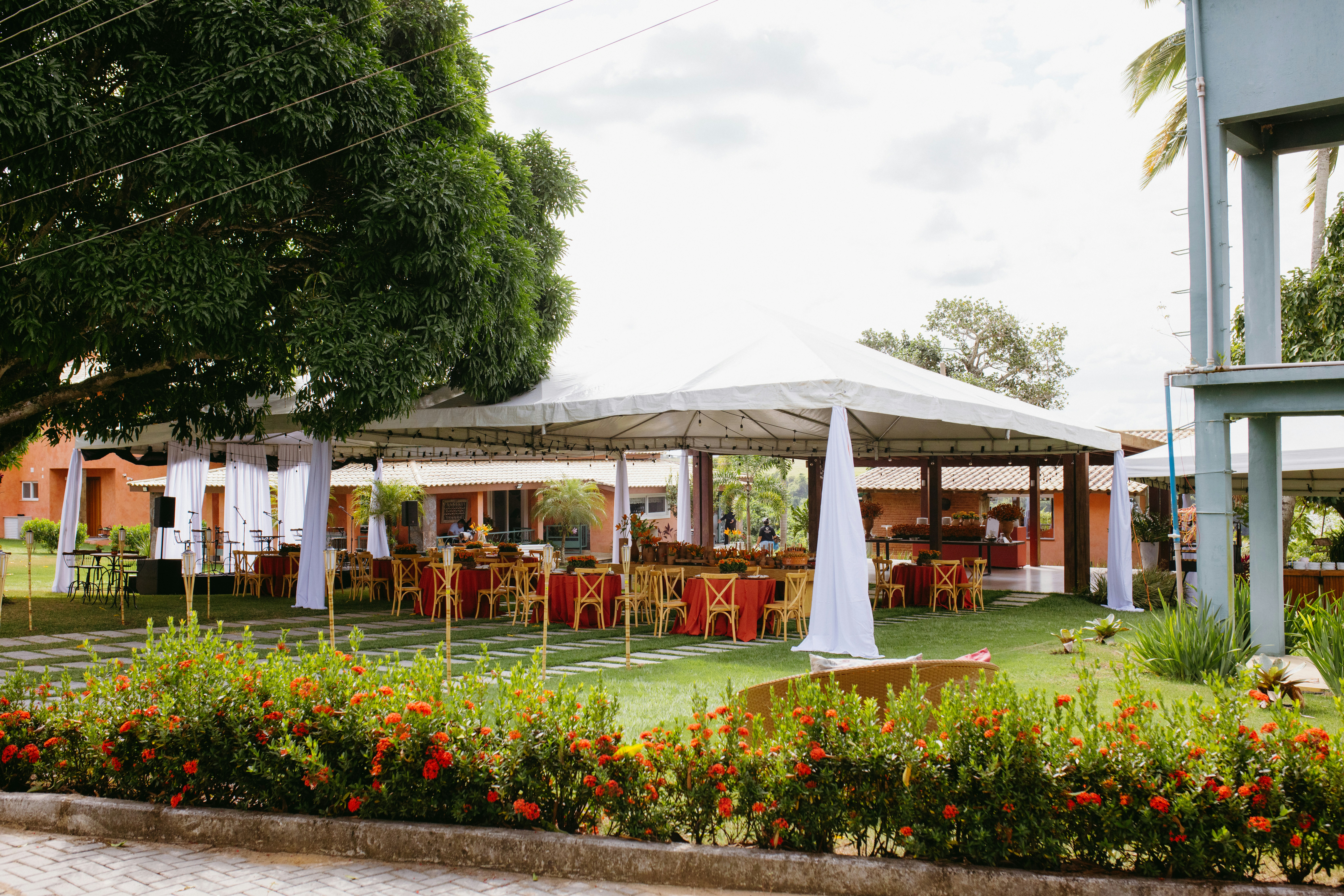 Tented outdoor event with striped canopies and lounge dining under a manicured garden