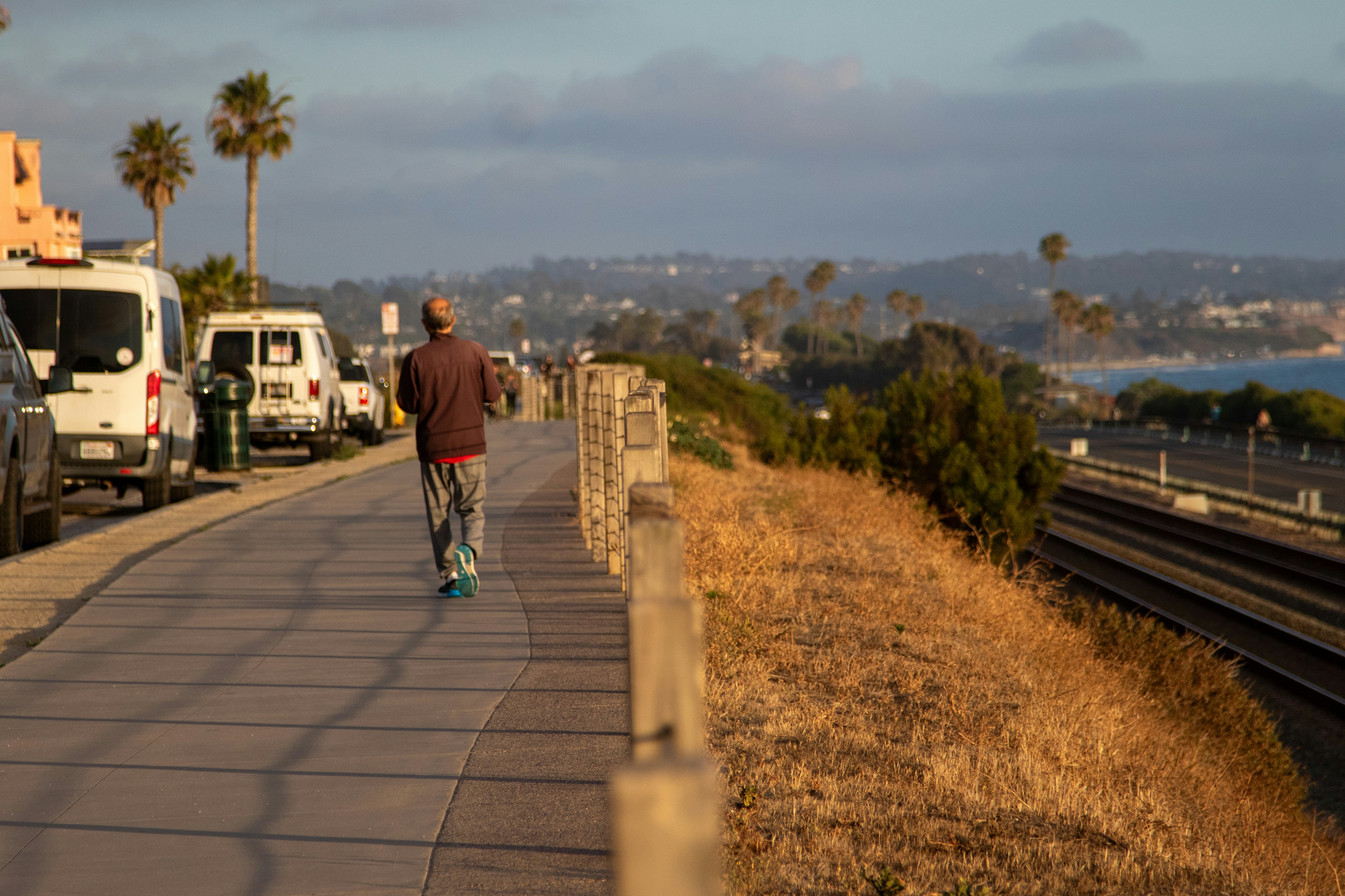 Pedestrian along sunlit coastal promenade