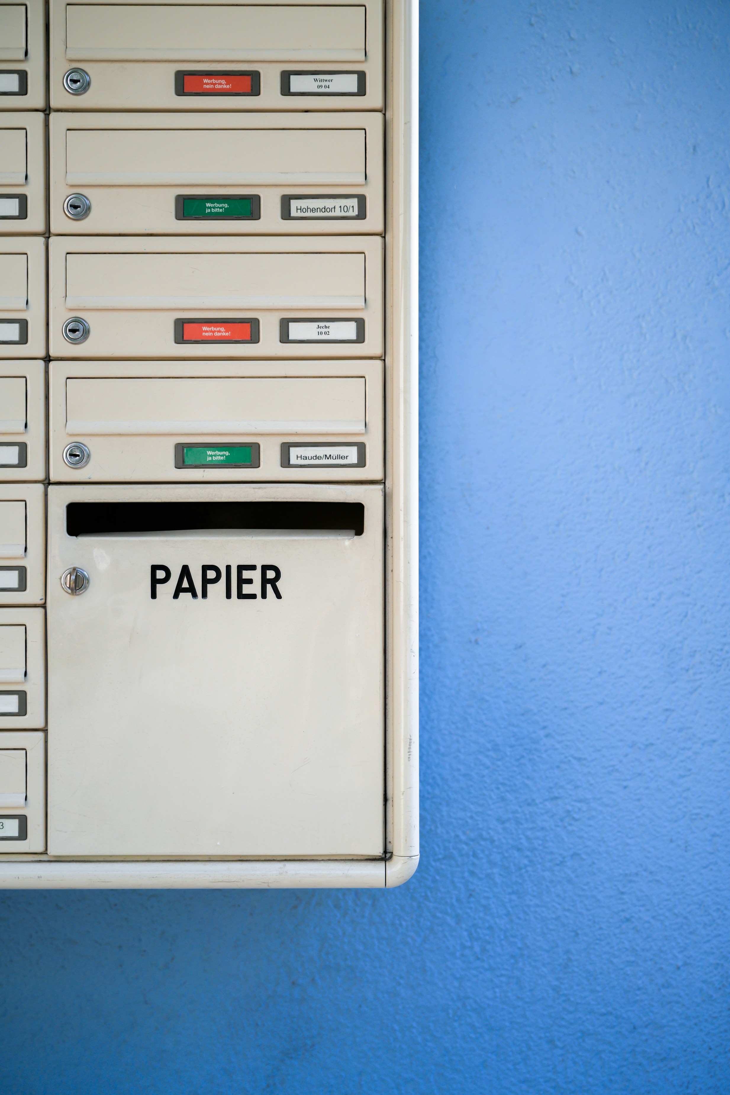 Blue wall and beige mailboxes: a quiet row of letters