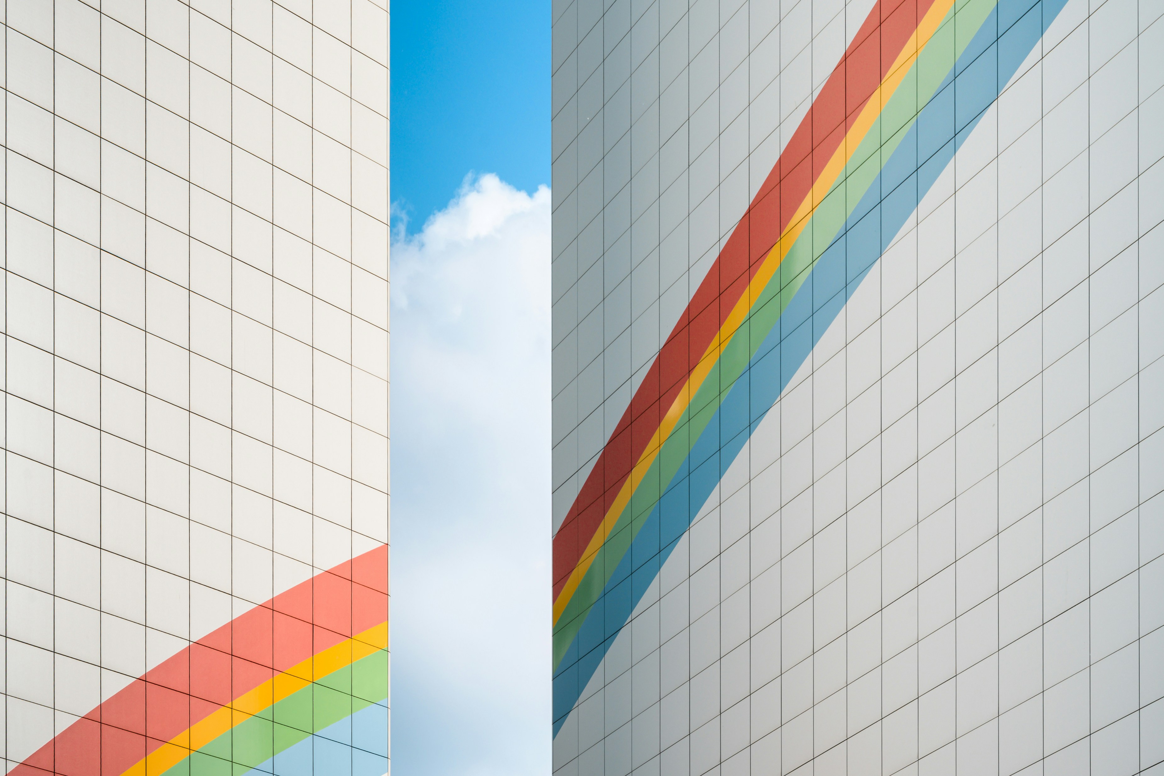White grid buildings featuring diagonal rainbow stripes against blue ...
