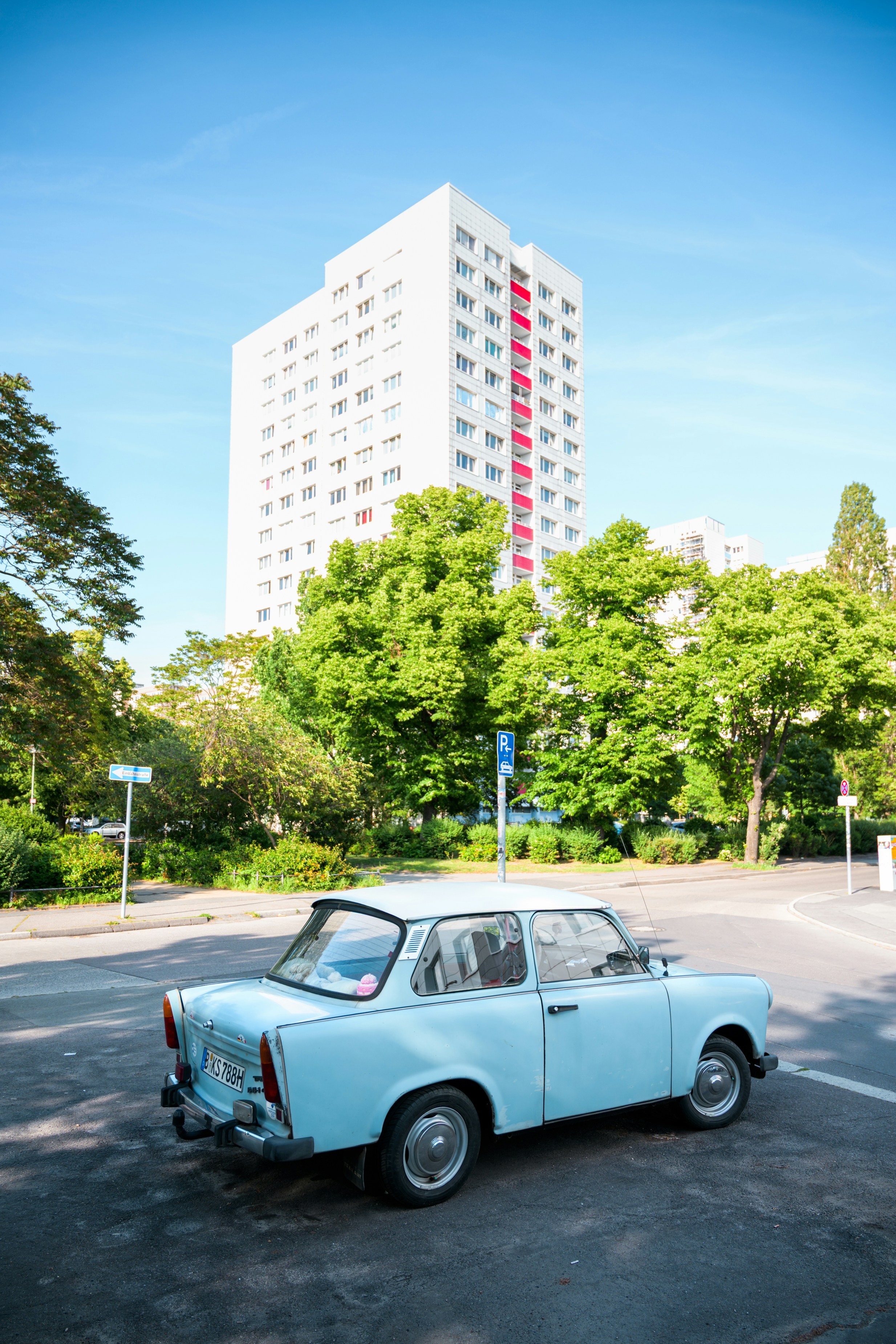 Blue vintage sedan under the cityscape trees