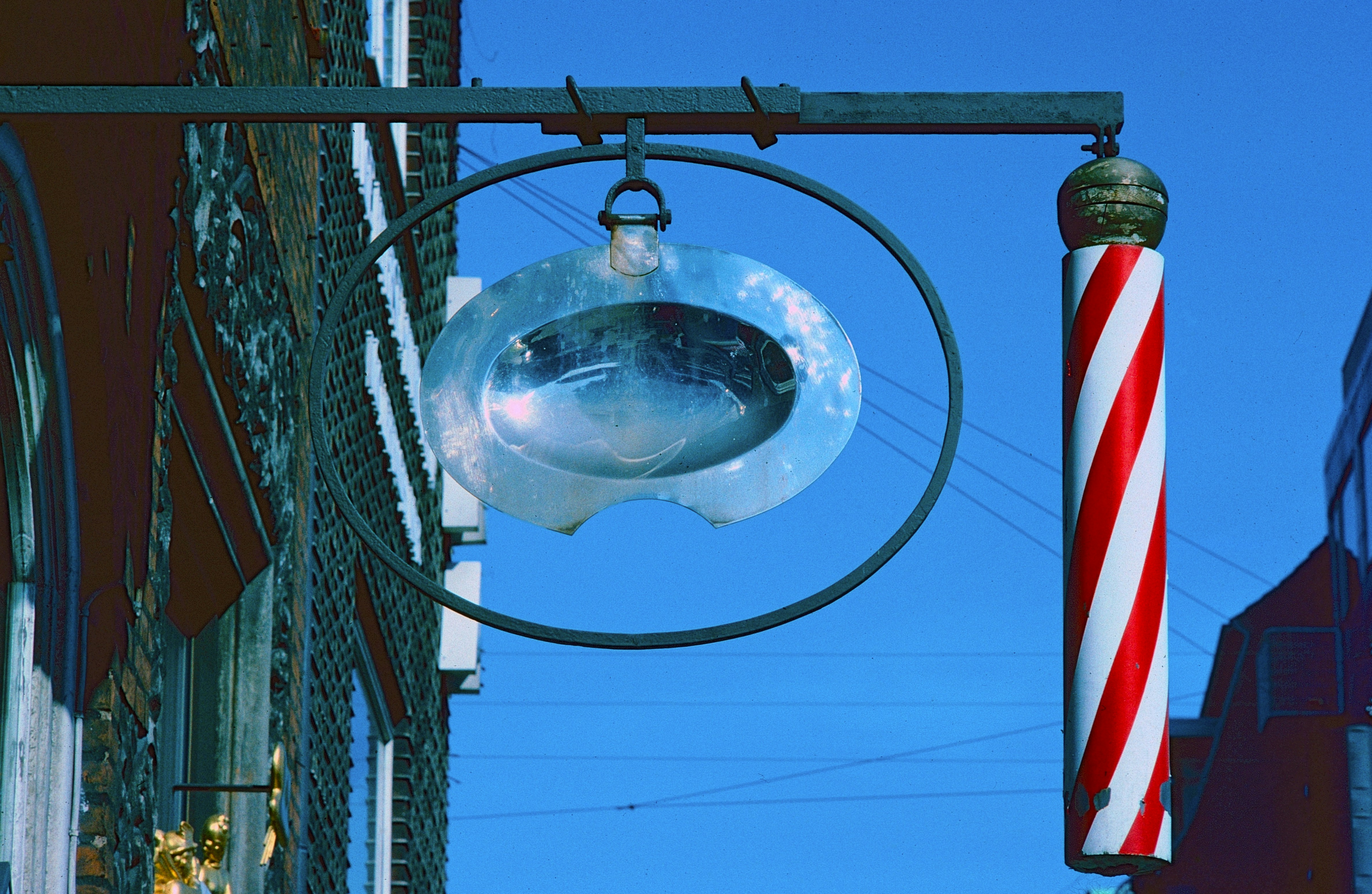 Circular Neon Light Over a Striped Barbershop Bar Sign in Clear Blue Day