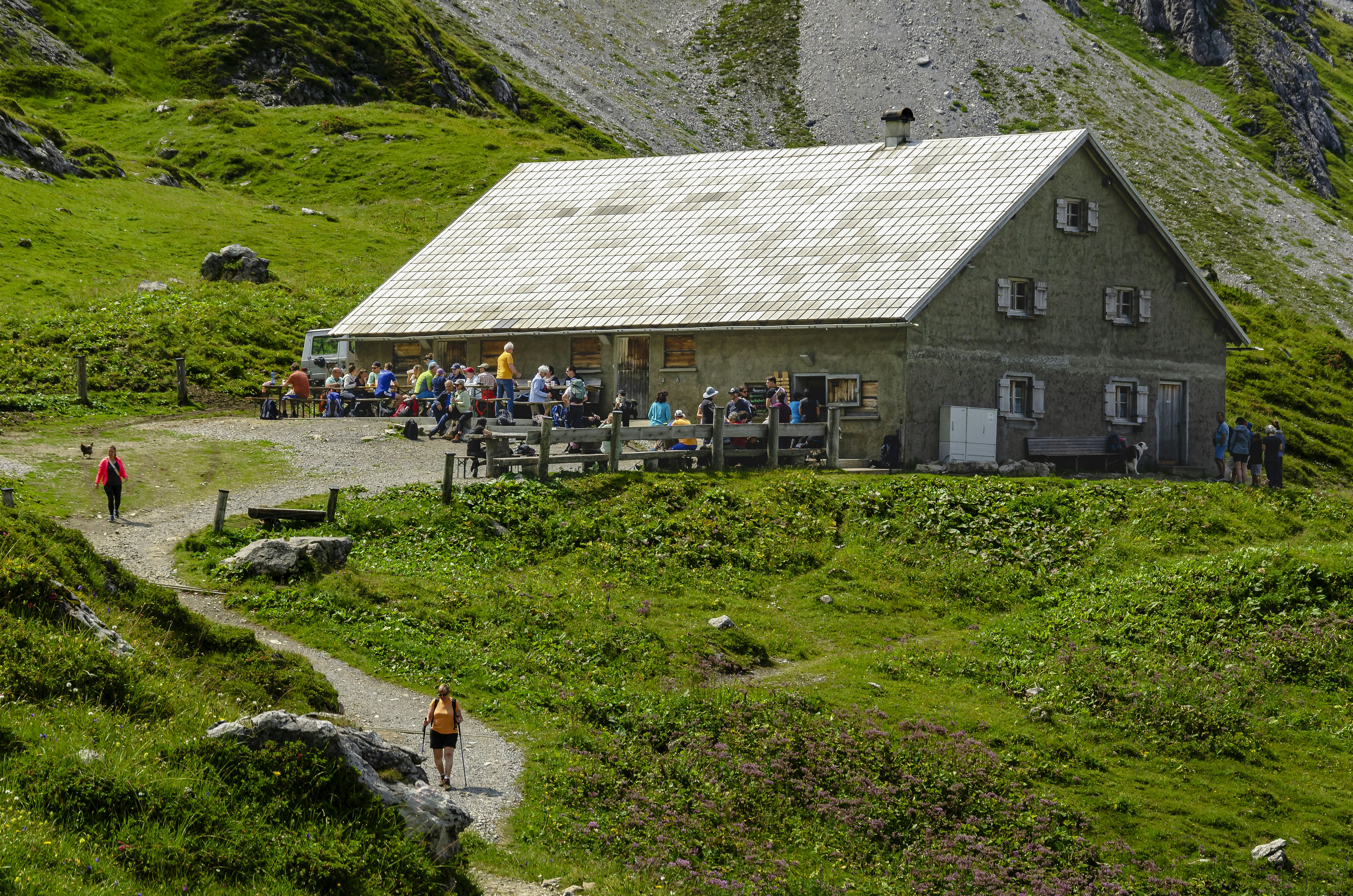 Hikers at a Mountain Refuge: A Sunny Trek to the Stone Cabin