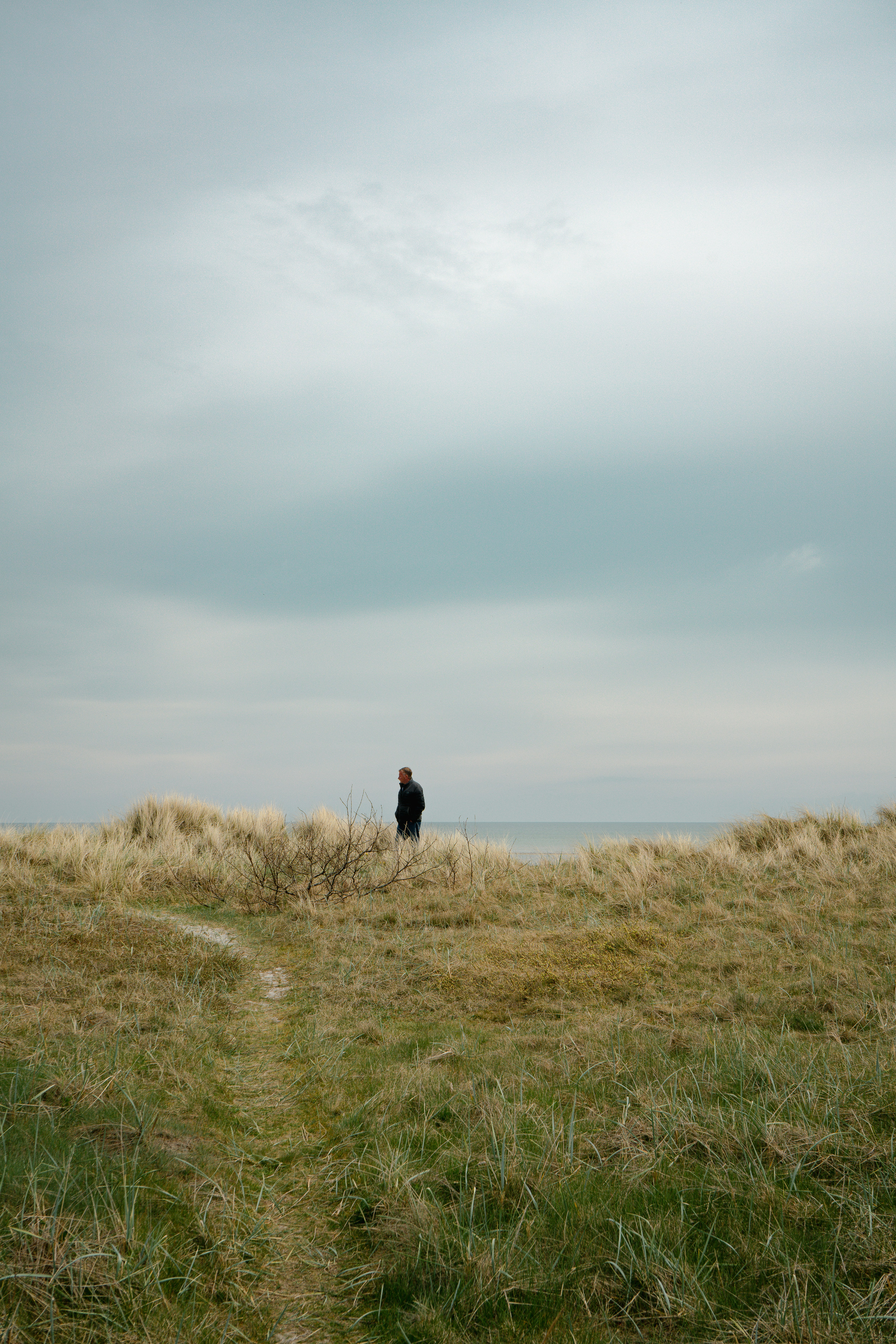  lone figure on dune path toward the sea under expansive sky