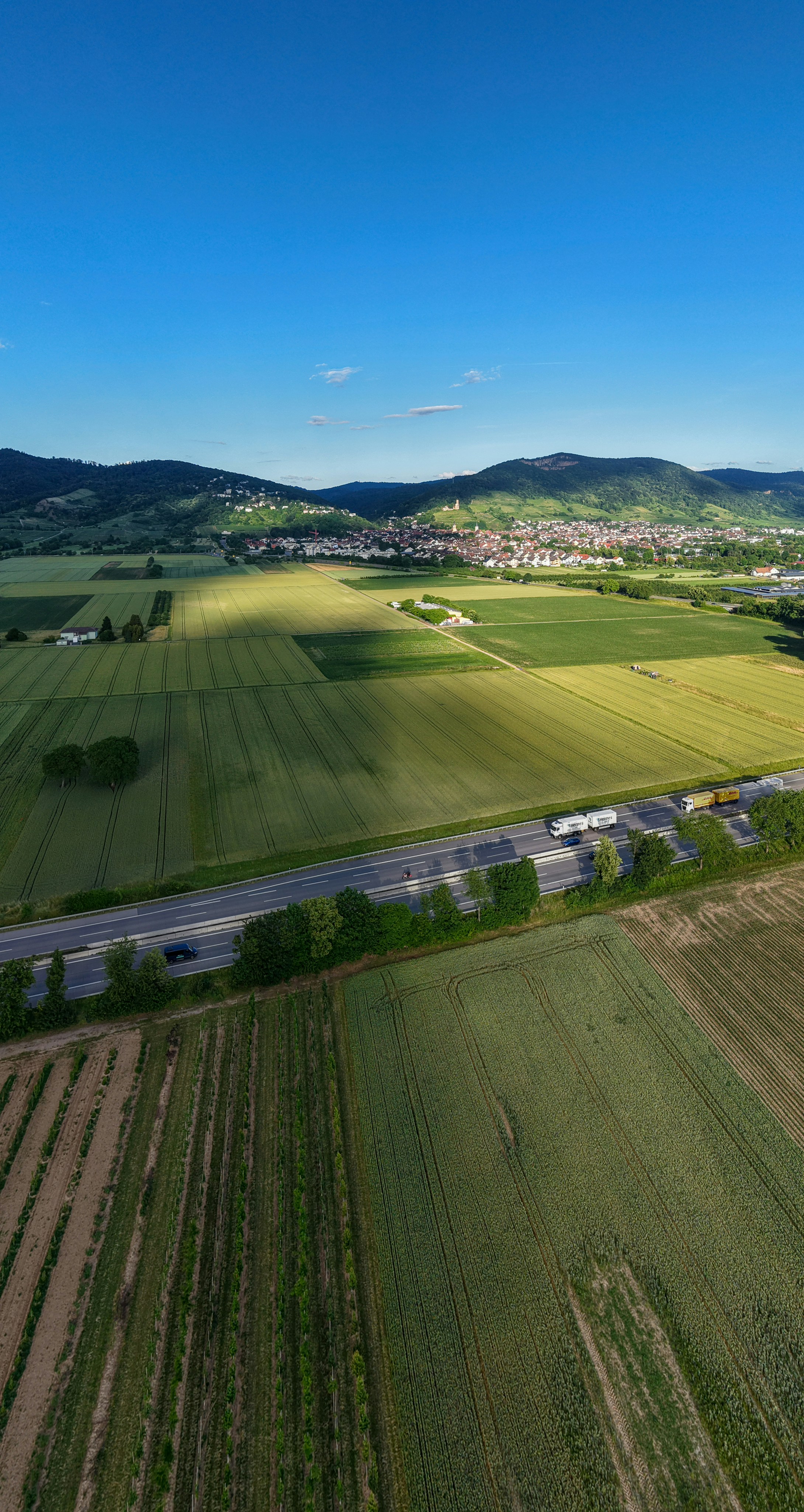 Green fields, highway, and distant town nestled among rolling hills.