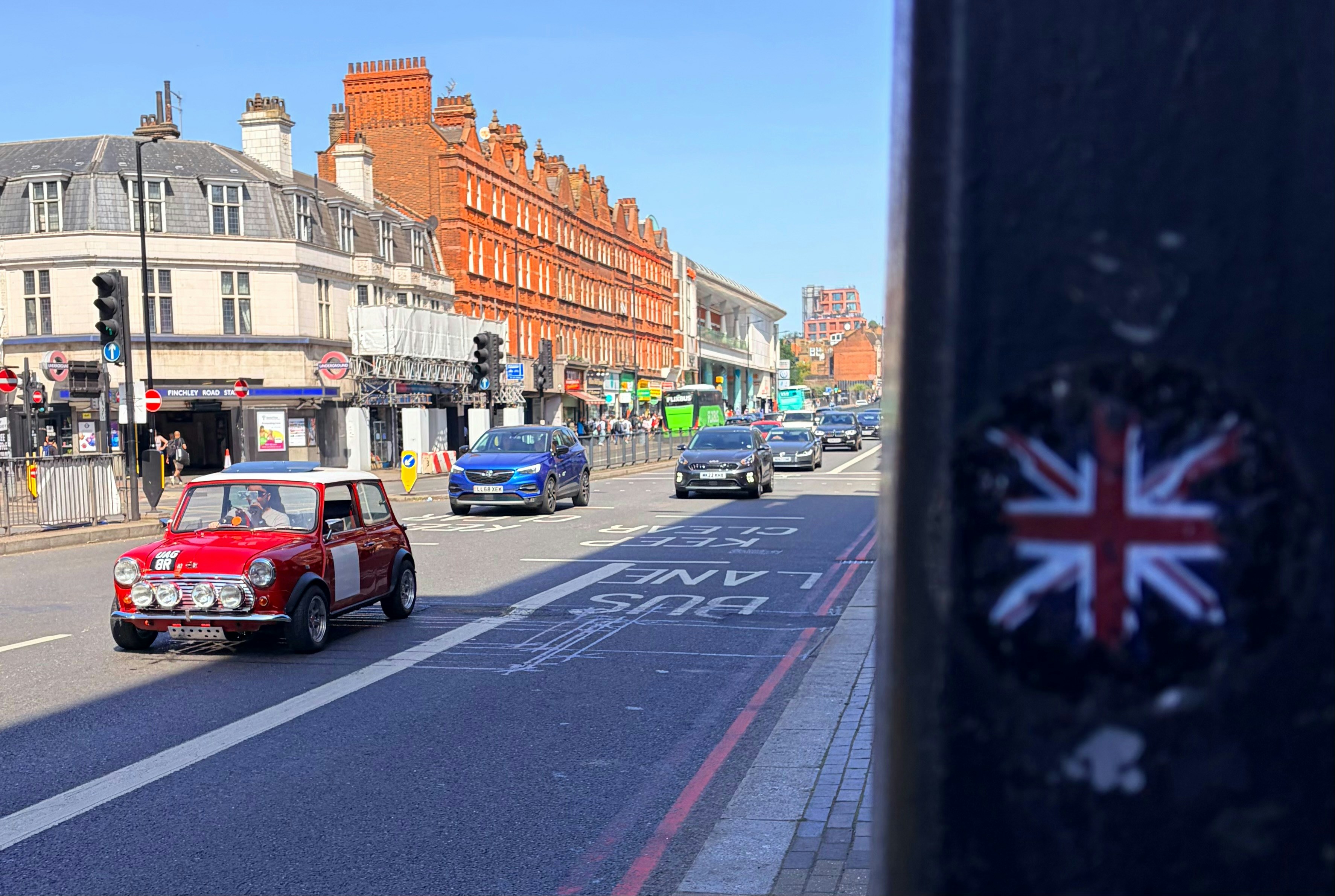 Sunny city street with a red mini cooper and buildings.