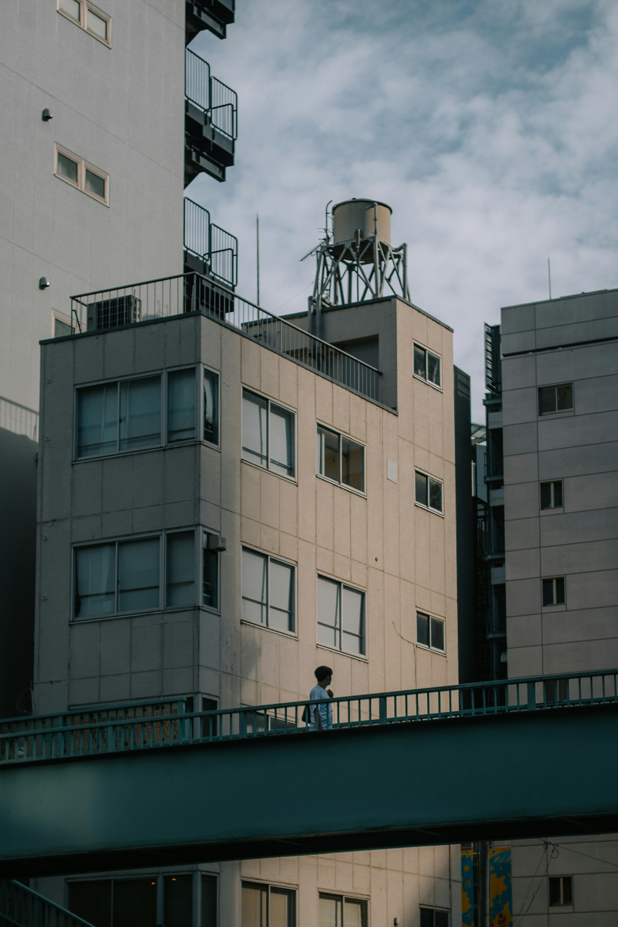 Pedestrian Silhouette on a City Overpass Beneath Wall-Stacked Cubes