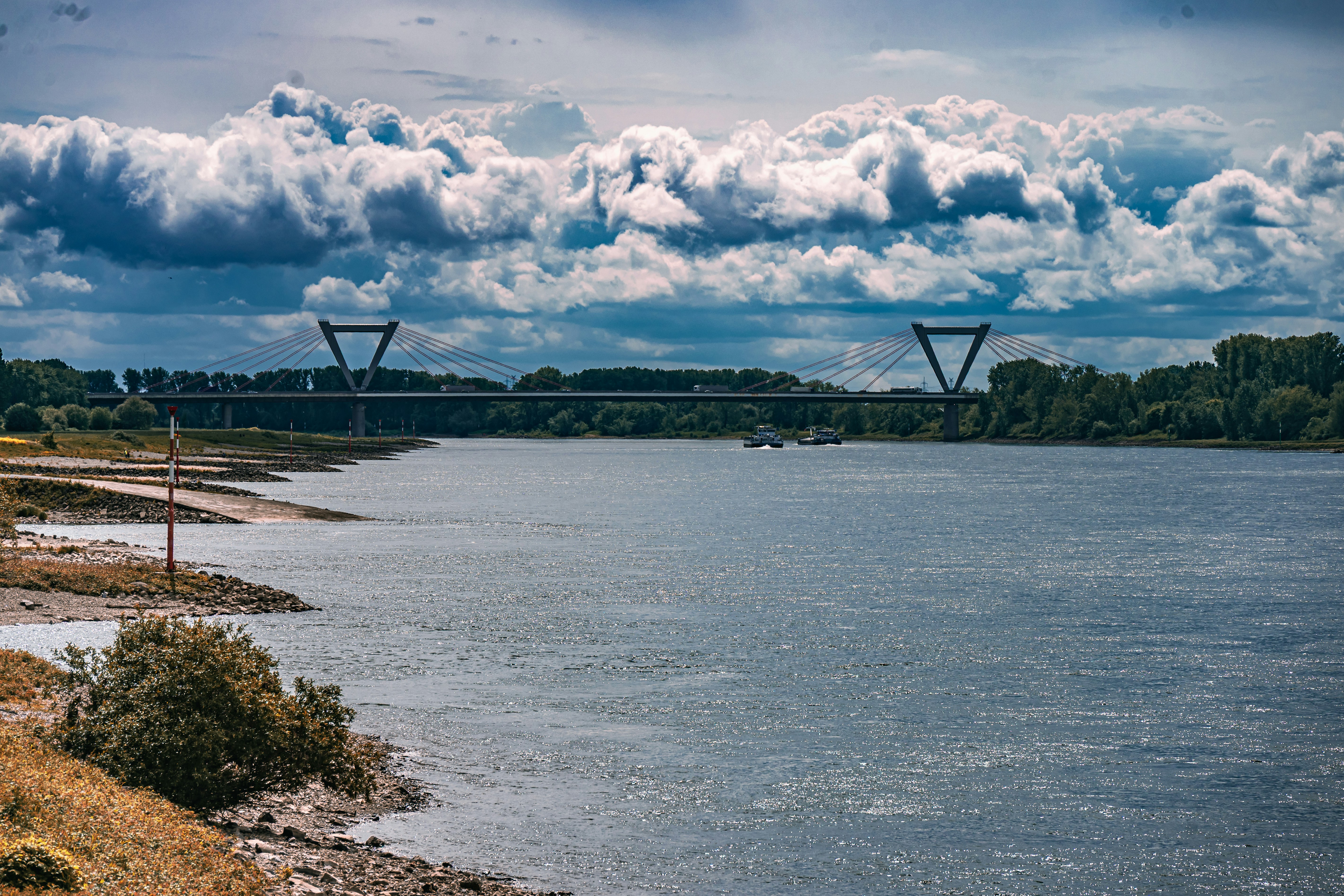 Bridge over calm river under dramatic cumulus clouds