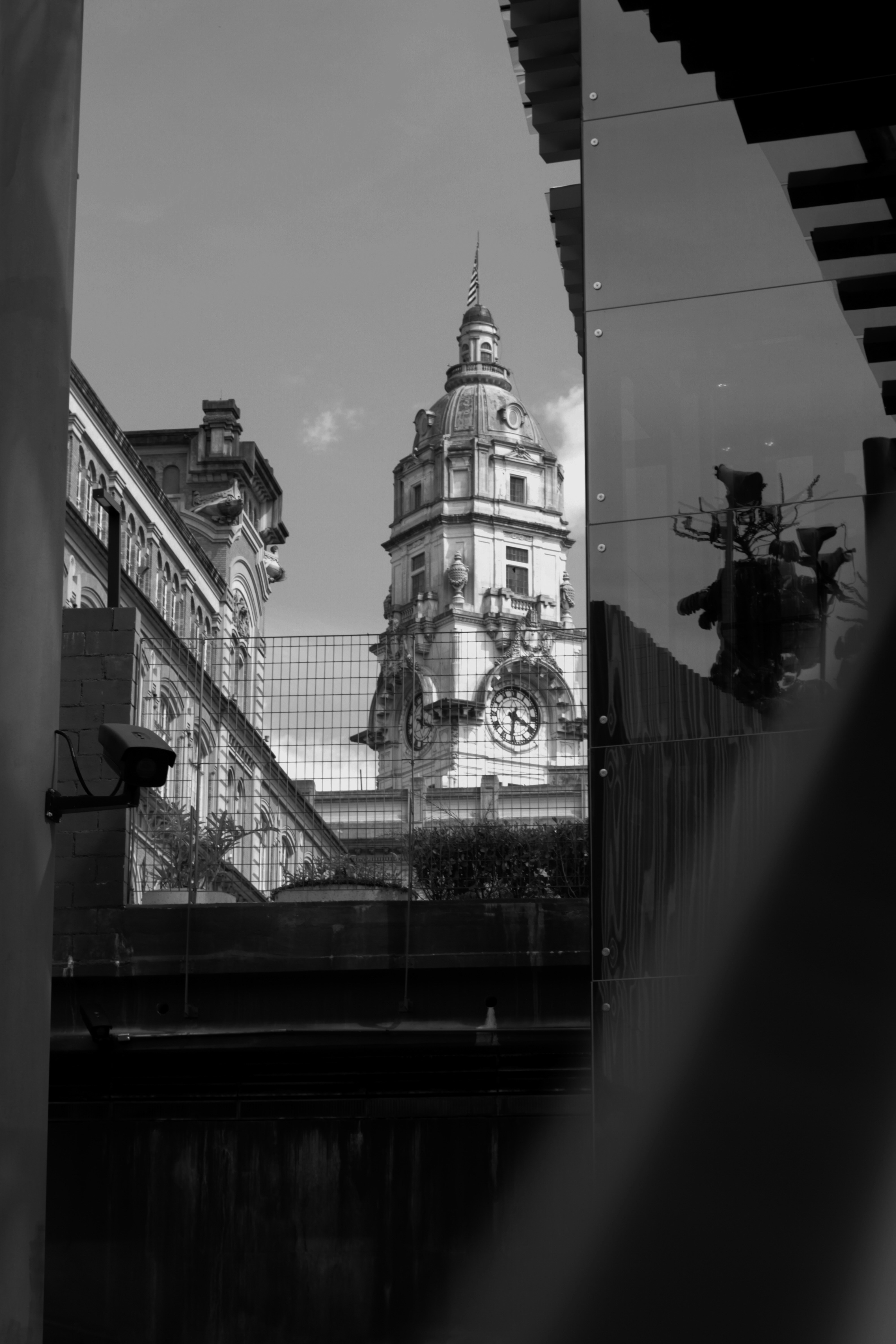 Clock tower framed by modern glass: a grayscale street study