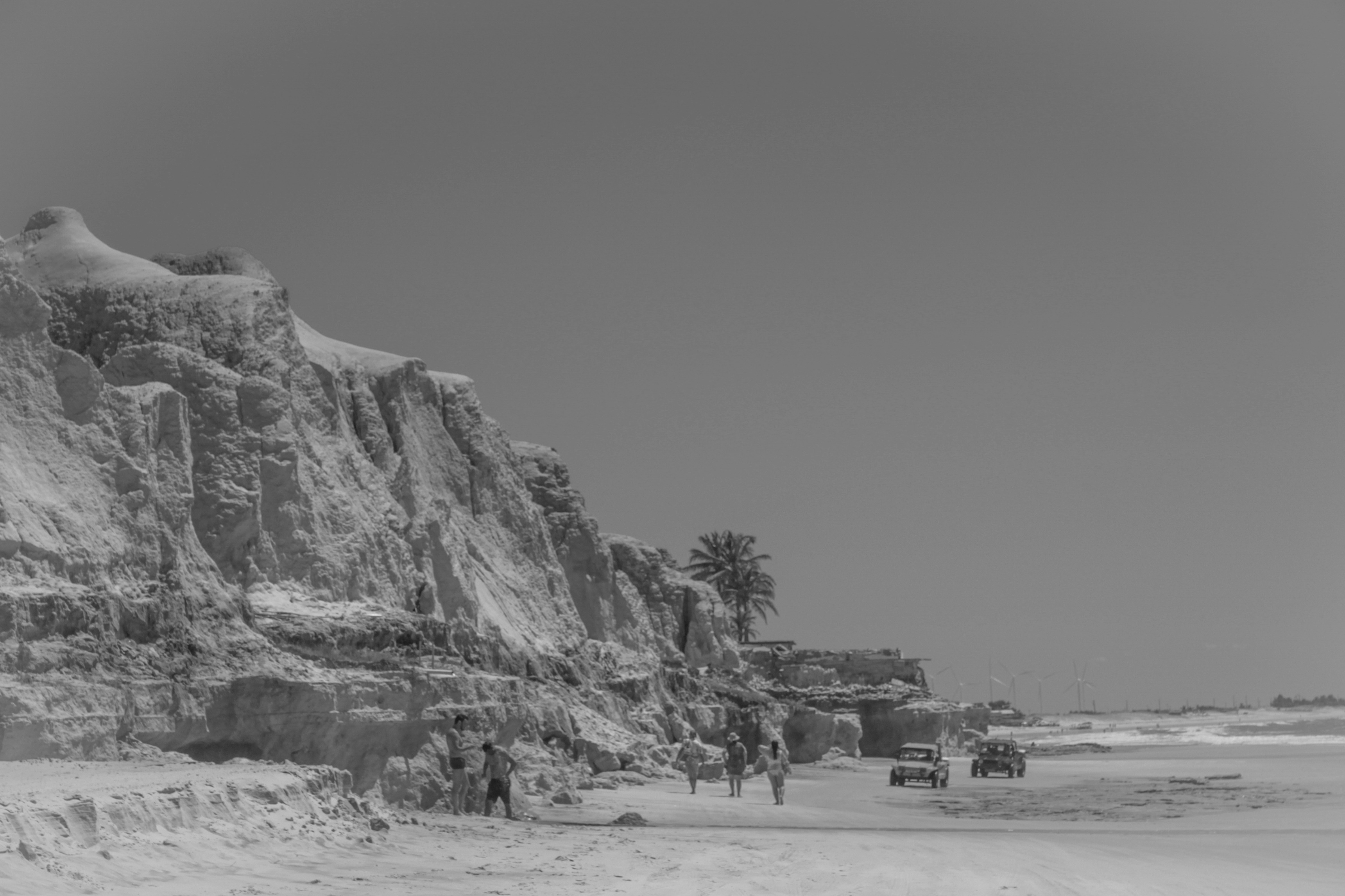 Rocky Cliffs and Beachgoers under a Quiet Sky