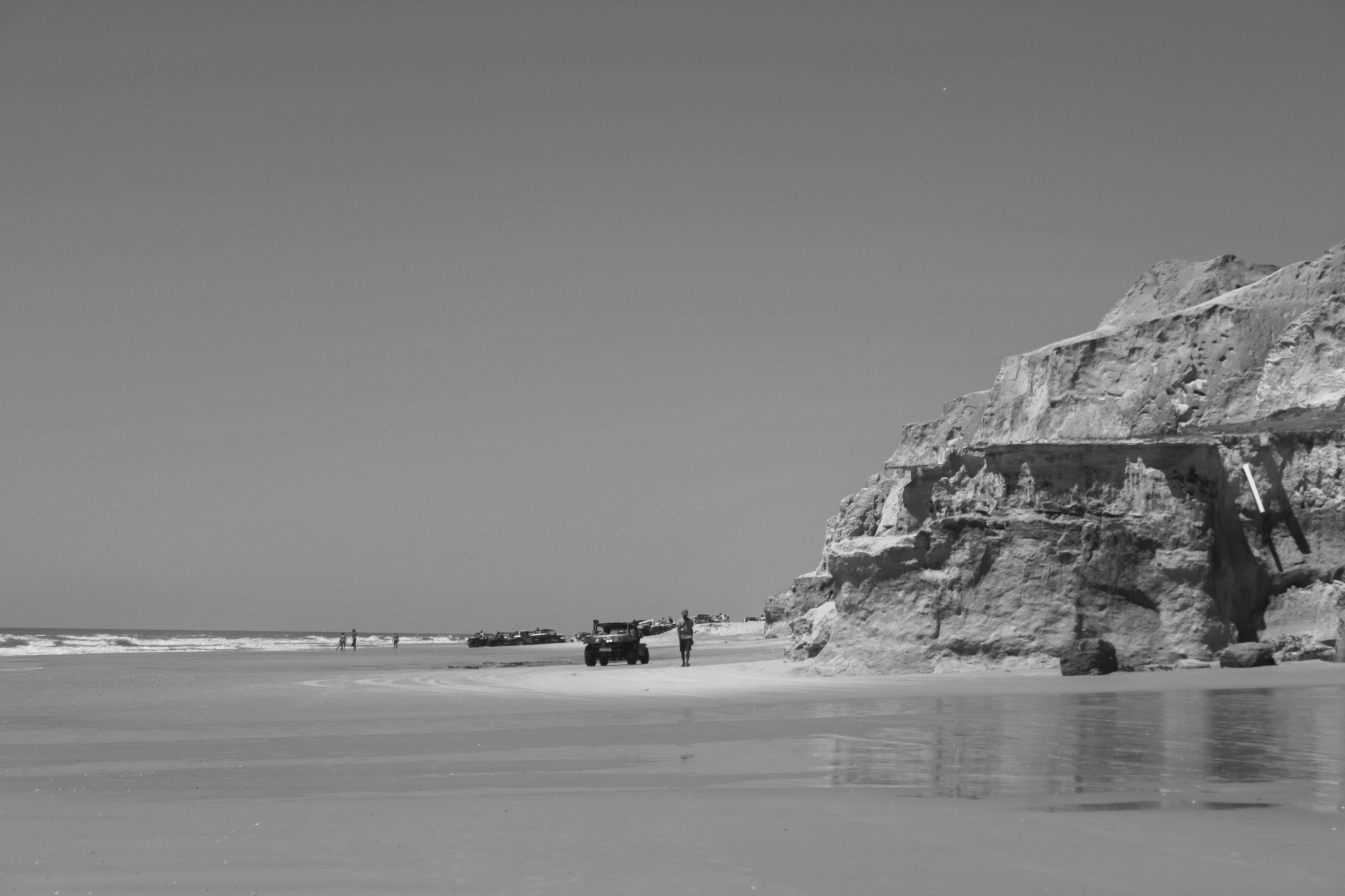 Coastal Silhouette: A Lone Vehicle and Figures on a Windward Shore