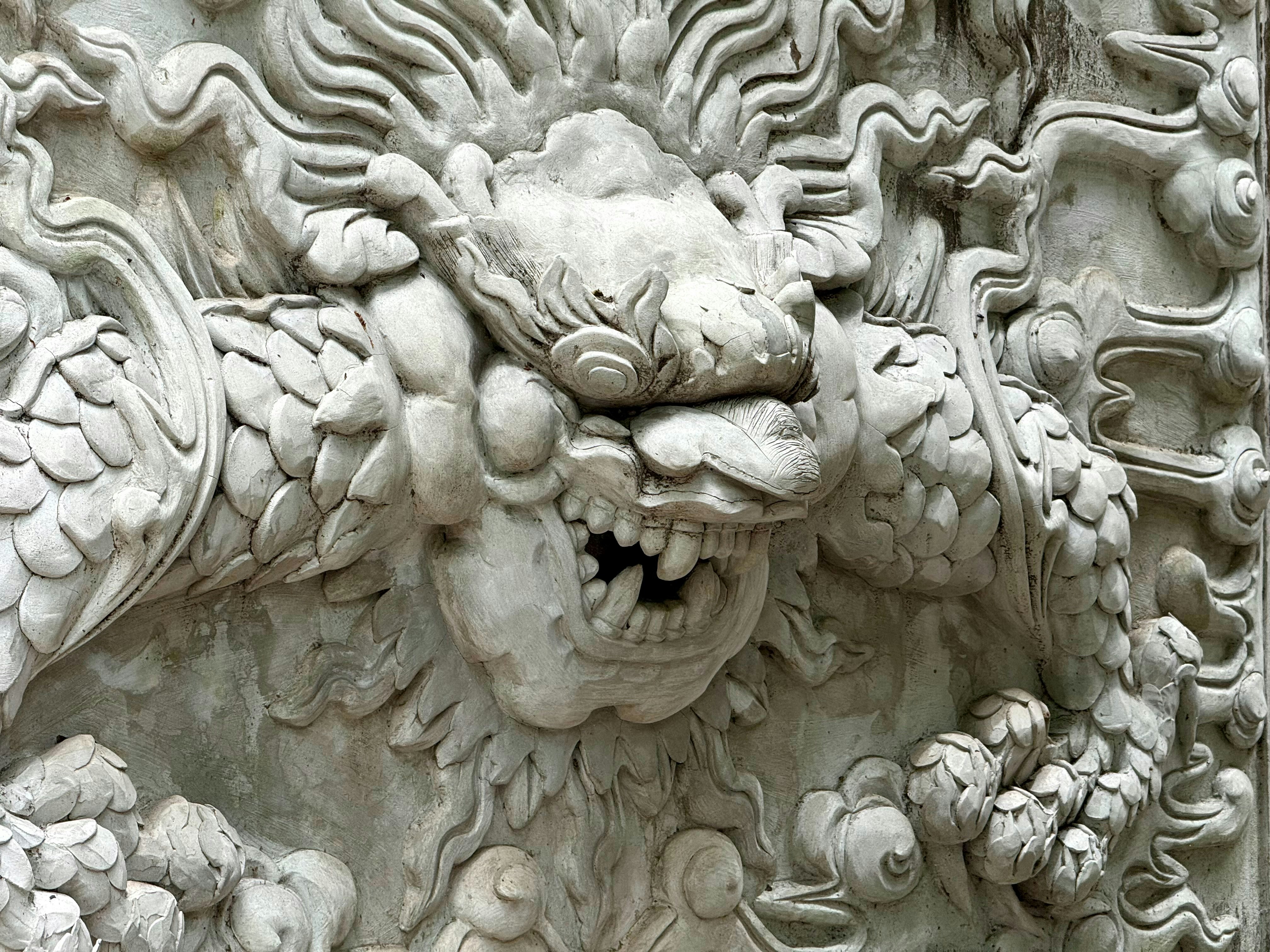 Detailed white stone carving of a fierce dragon's head.