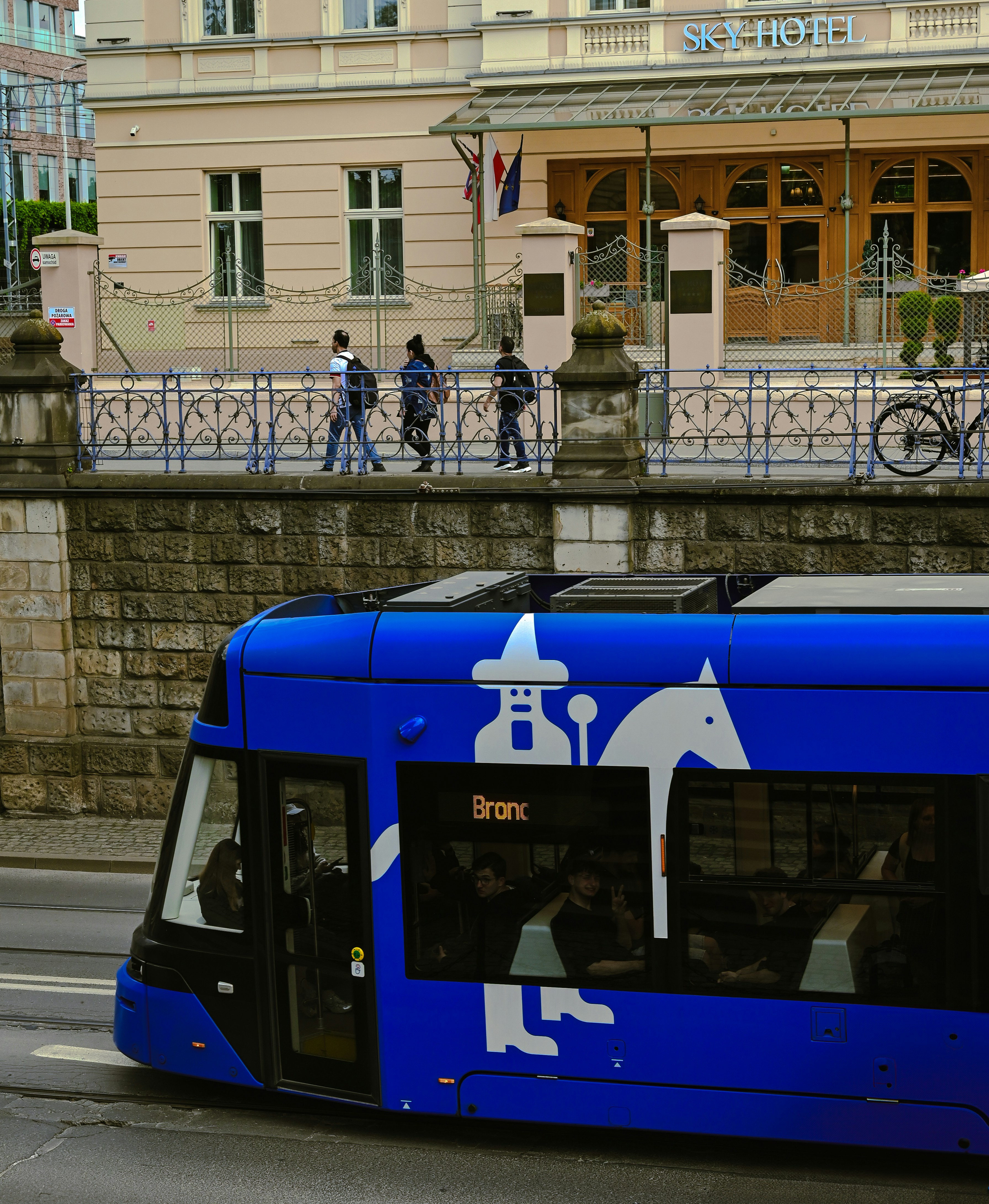 Blue tram gliding past a European hotel facade