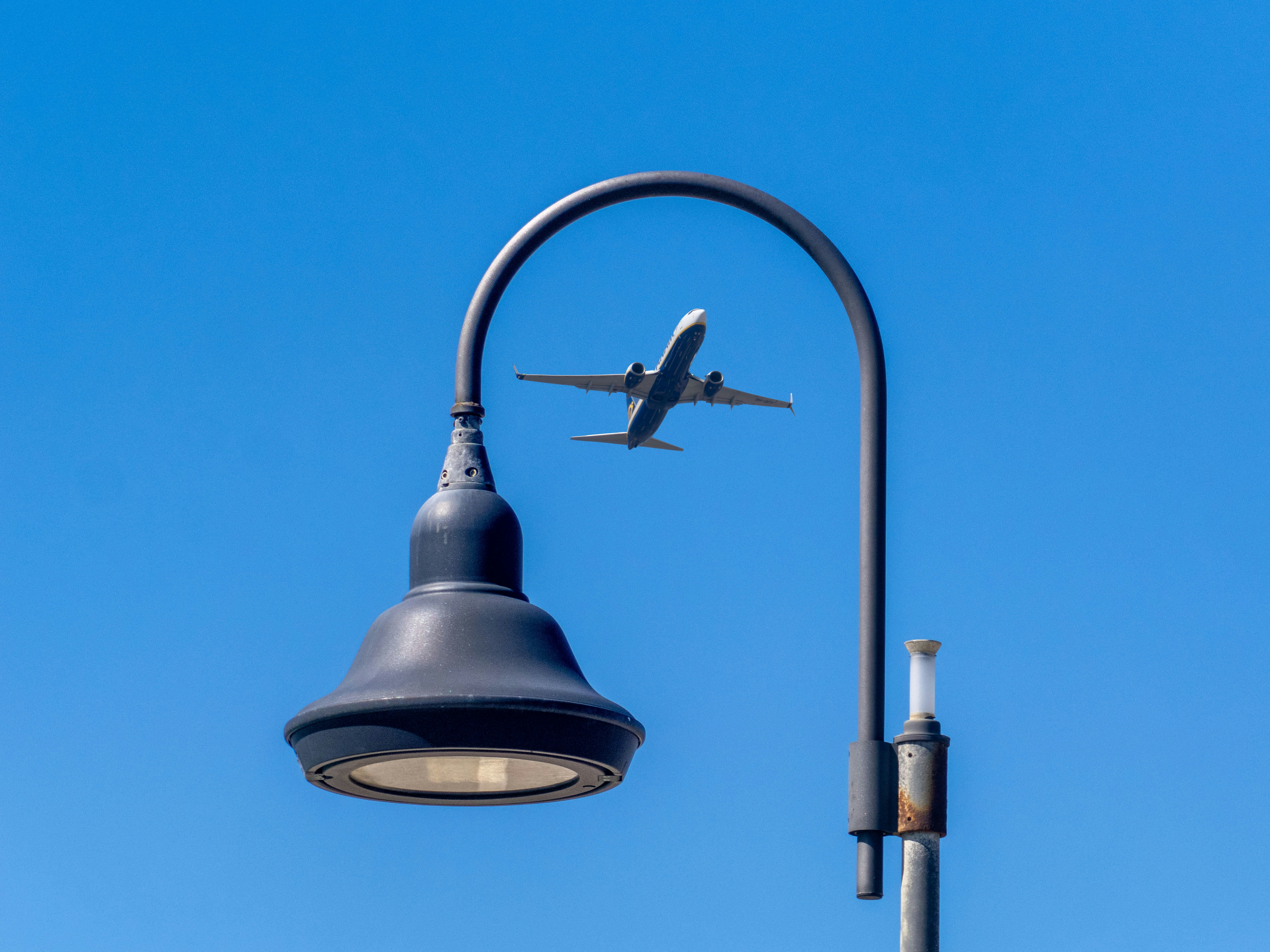 Midday Orbit: Airliner Crossing a Streetlamp
