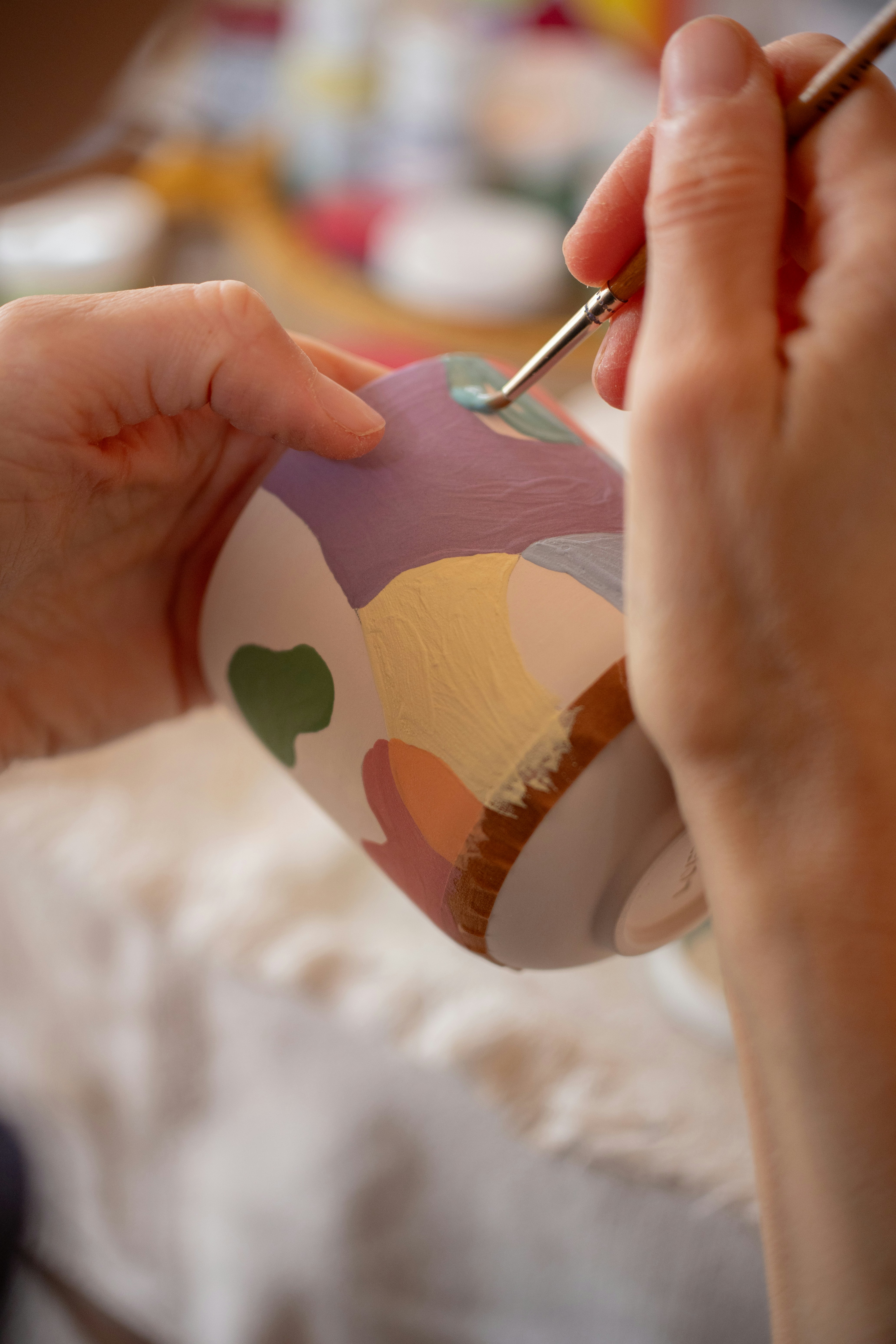 Palette in Progress: Hands Craft a Painted Vessel