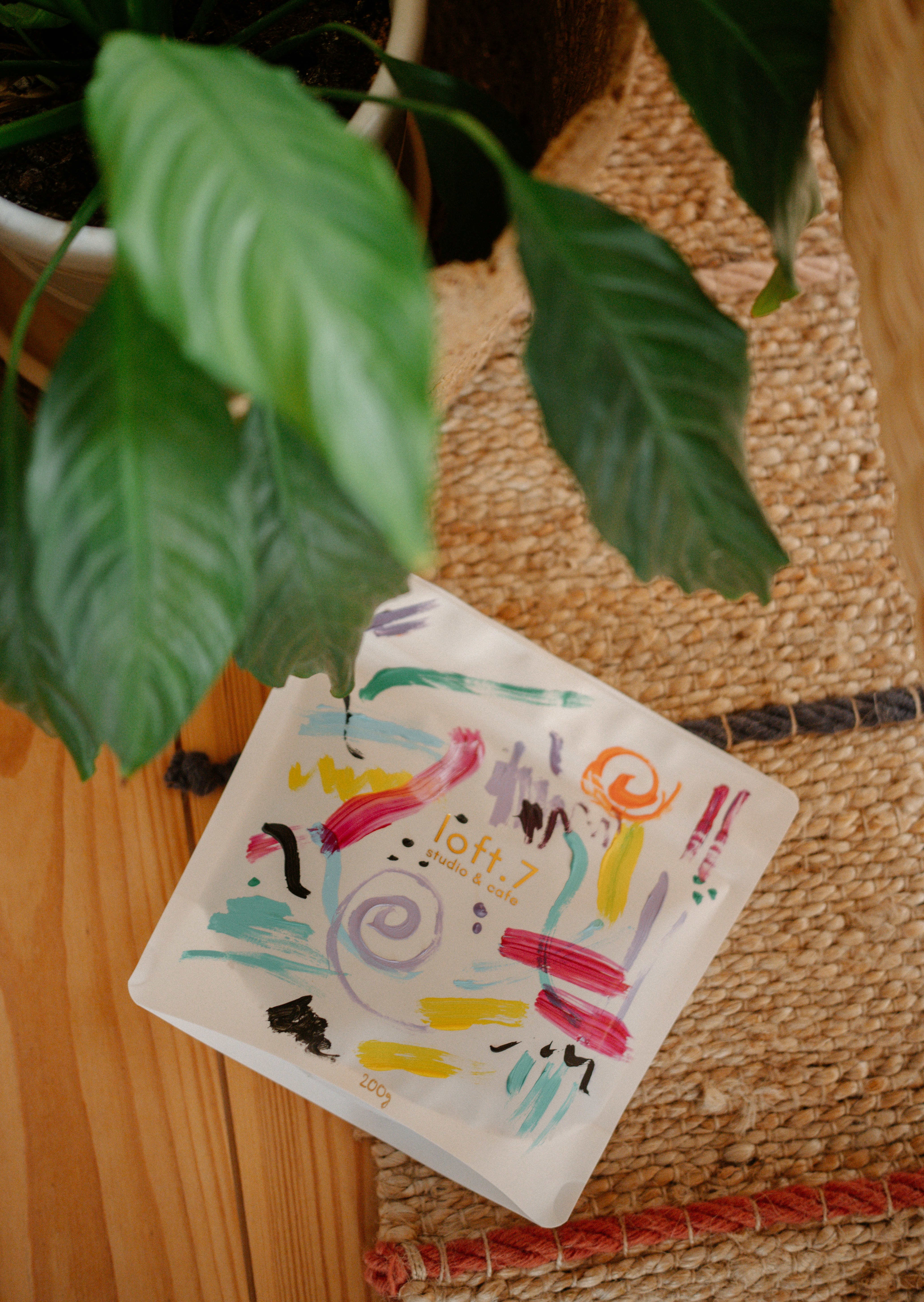 Abstract art package with a green plant and woven mat.