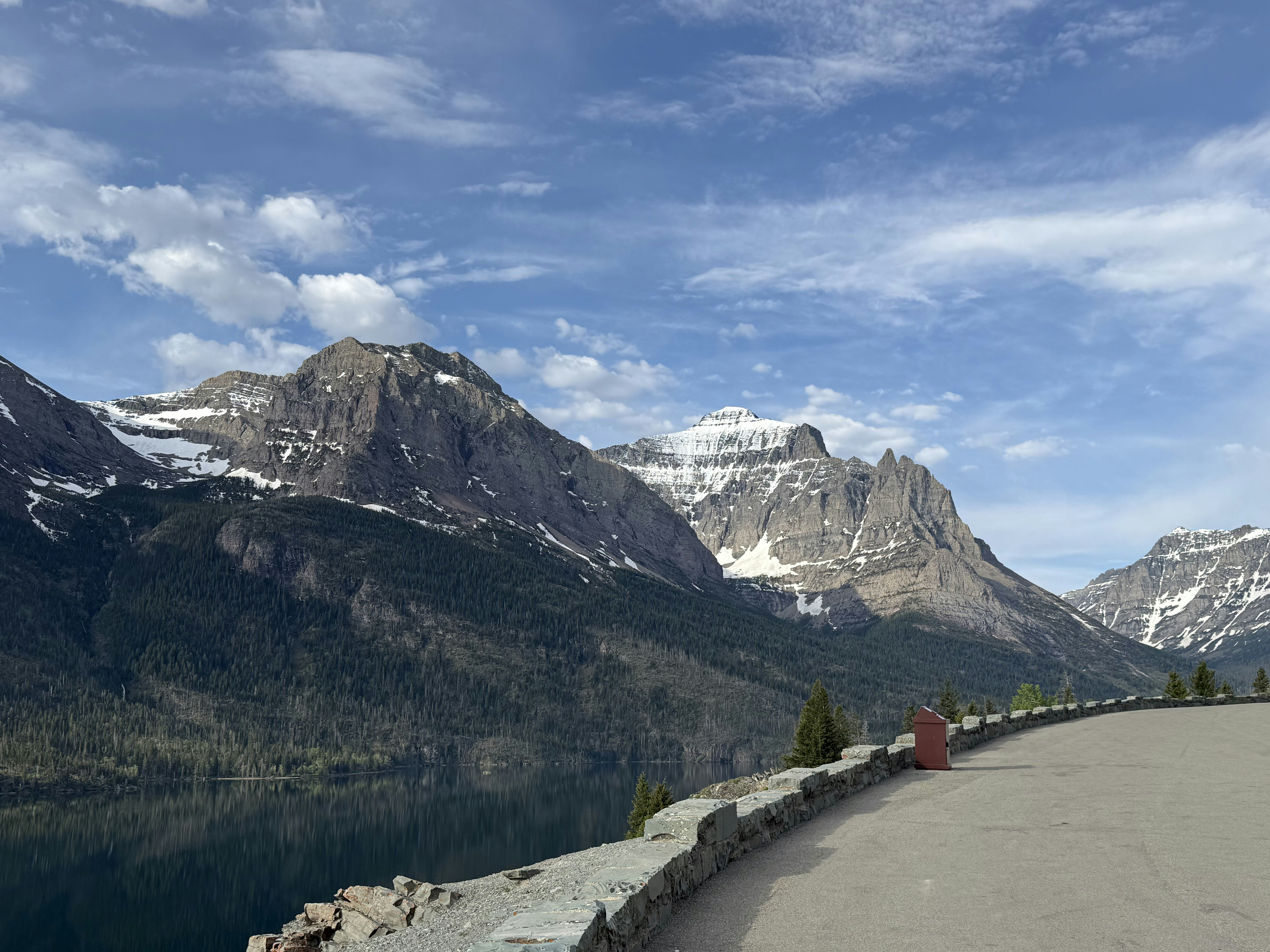 Snow-capped mountains, a tranquil lake, and a winding road.