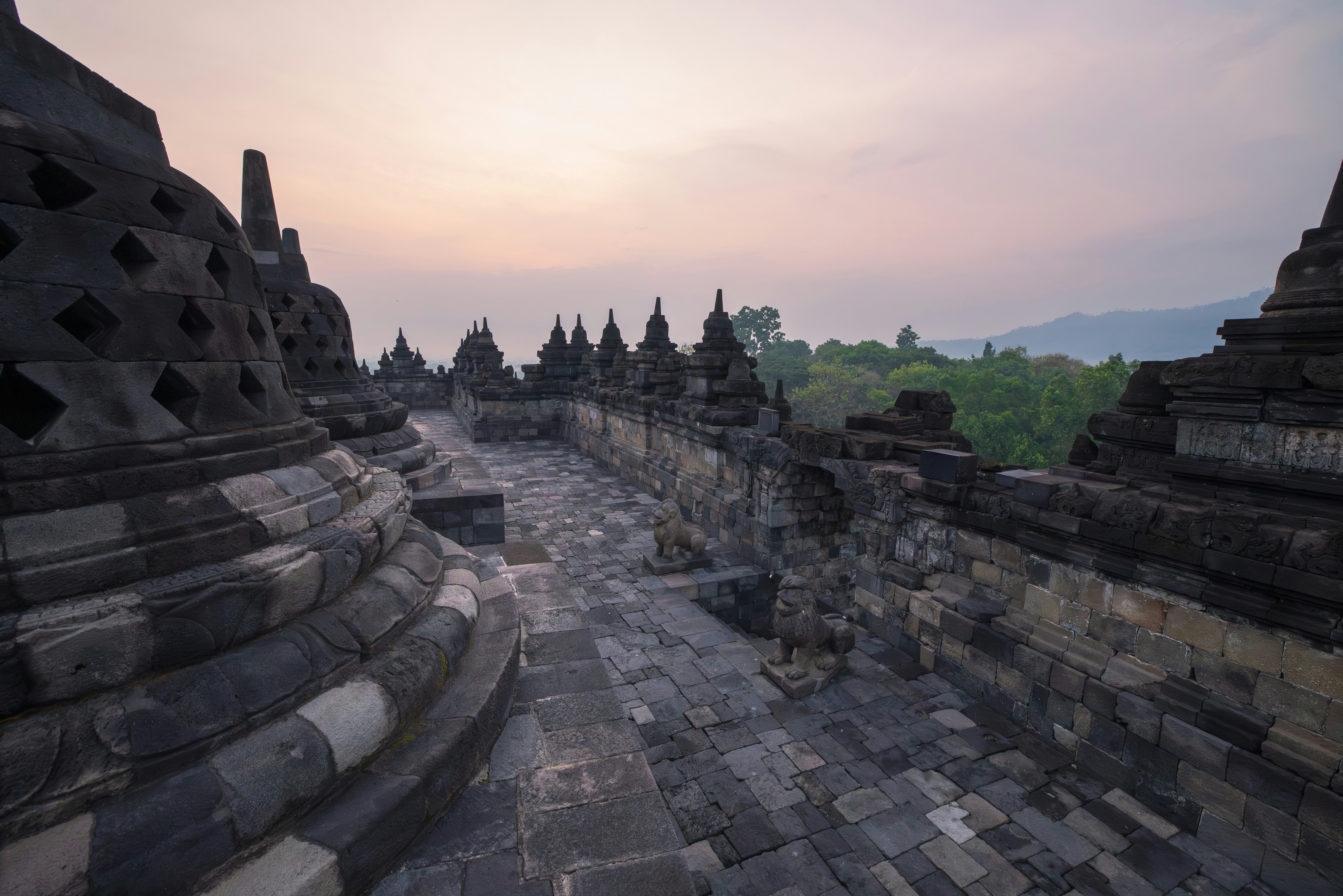 Ancient stone temple with stupas at sunrise.