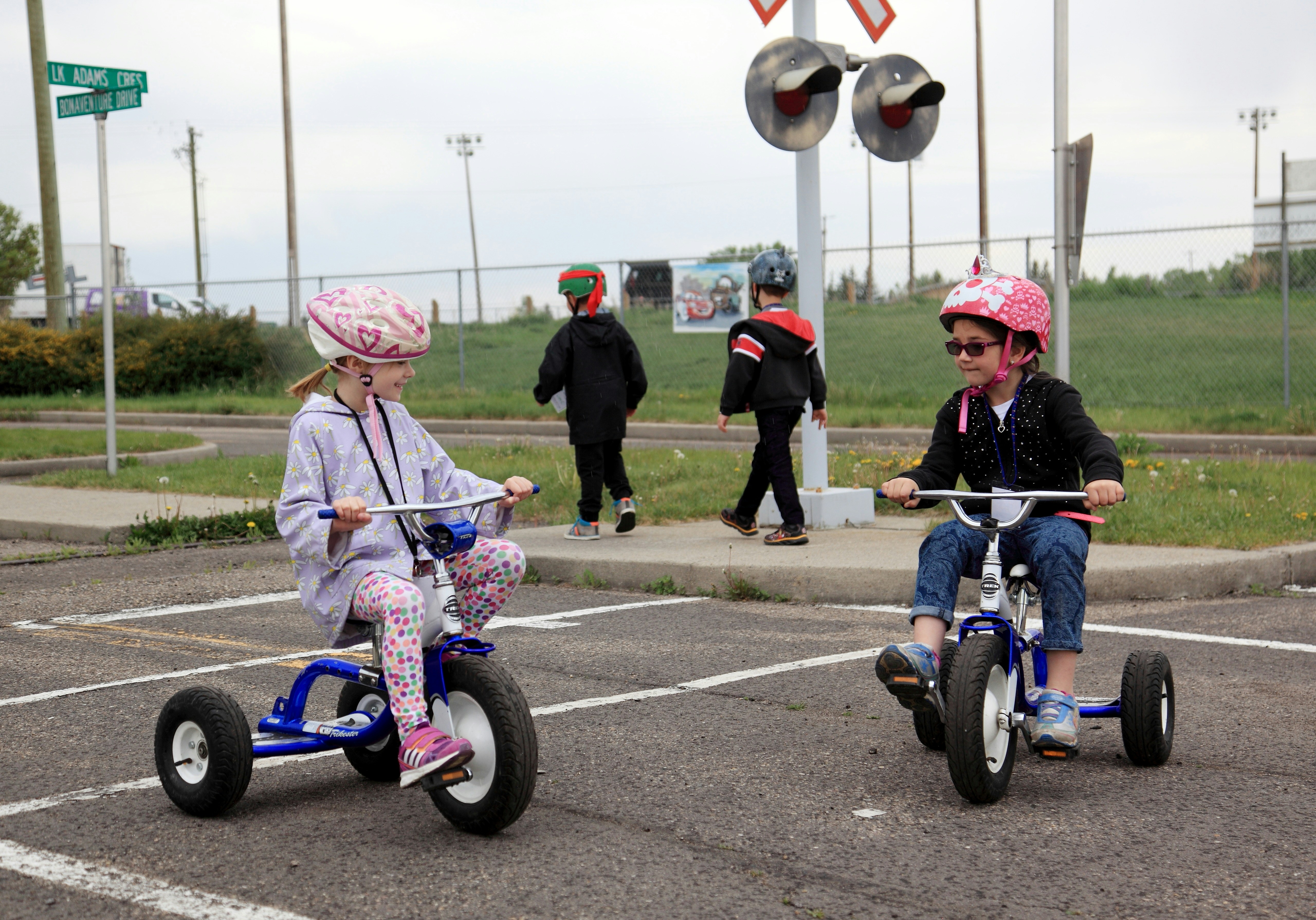 Two Tricolored Trikes in a Parking Lot Playground