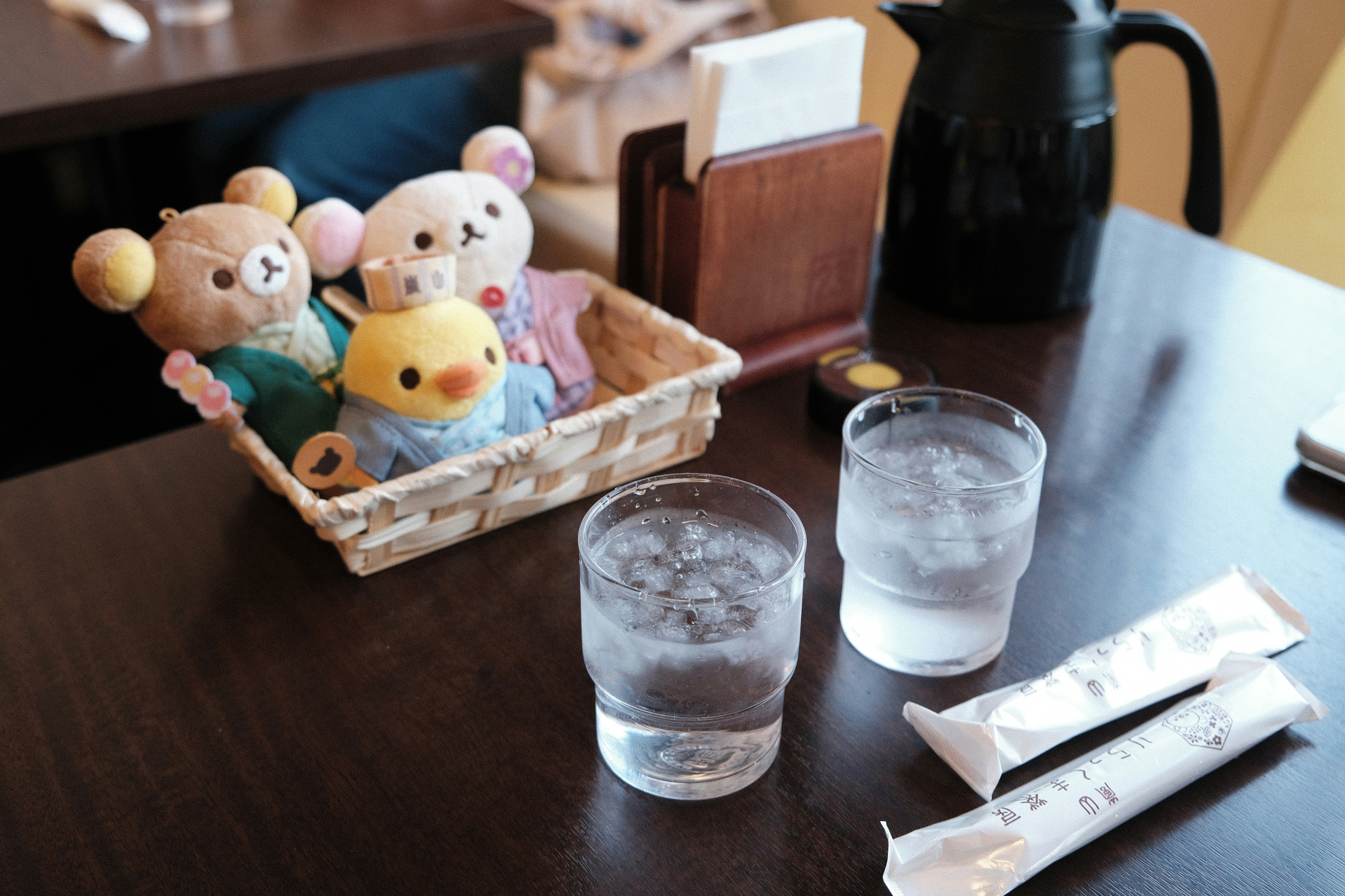Plush toys and water glasses on a wooden table.